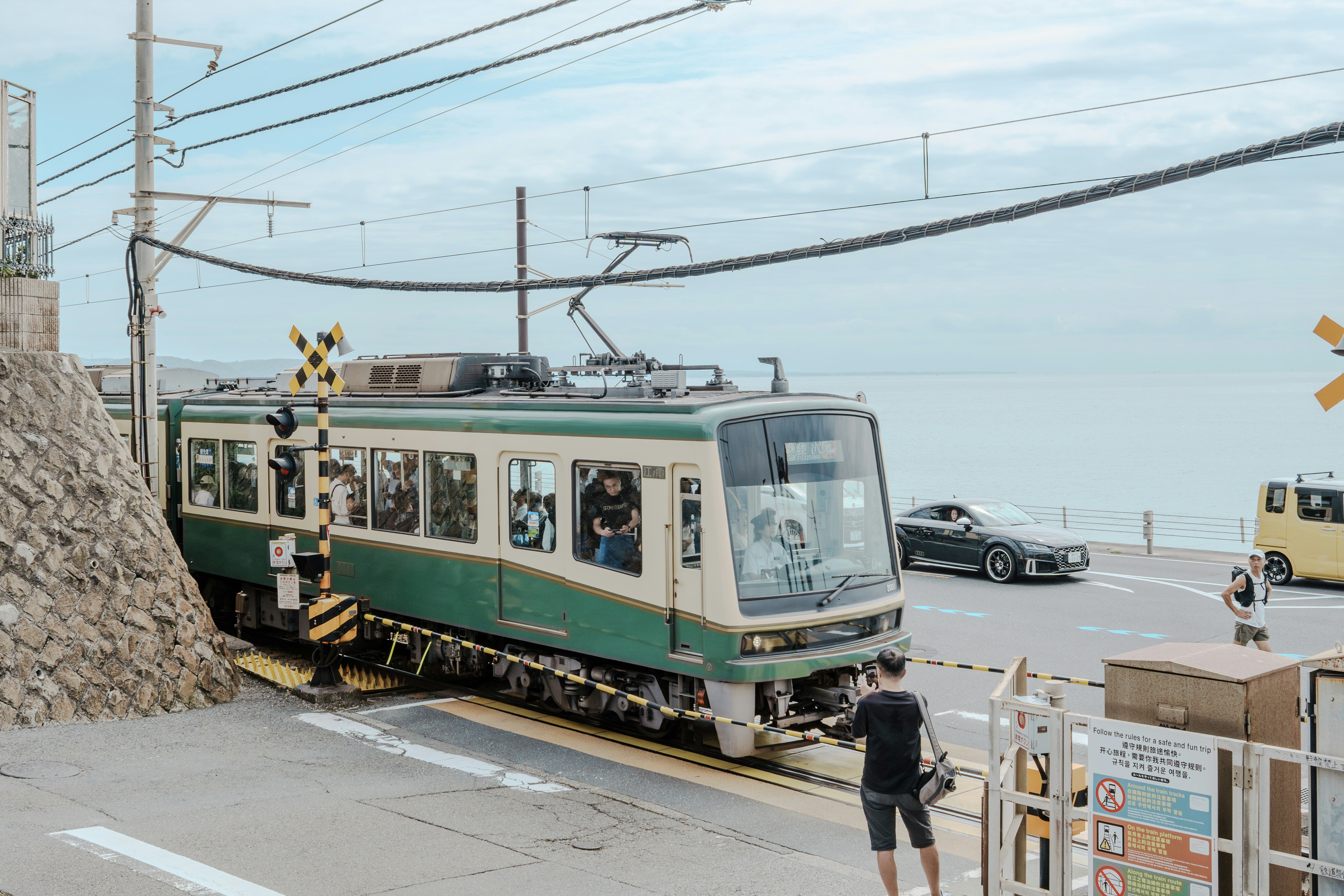 Coastal Tram at the Crossing: A Seaside Stop by the Rails