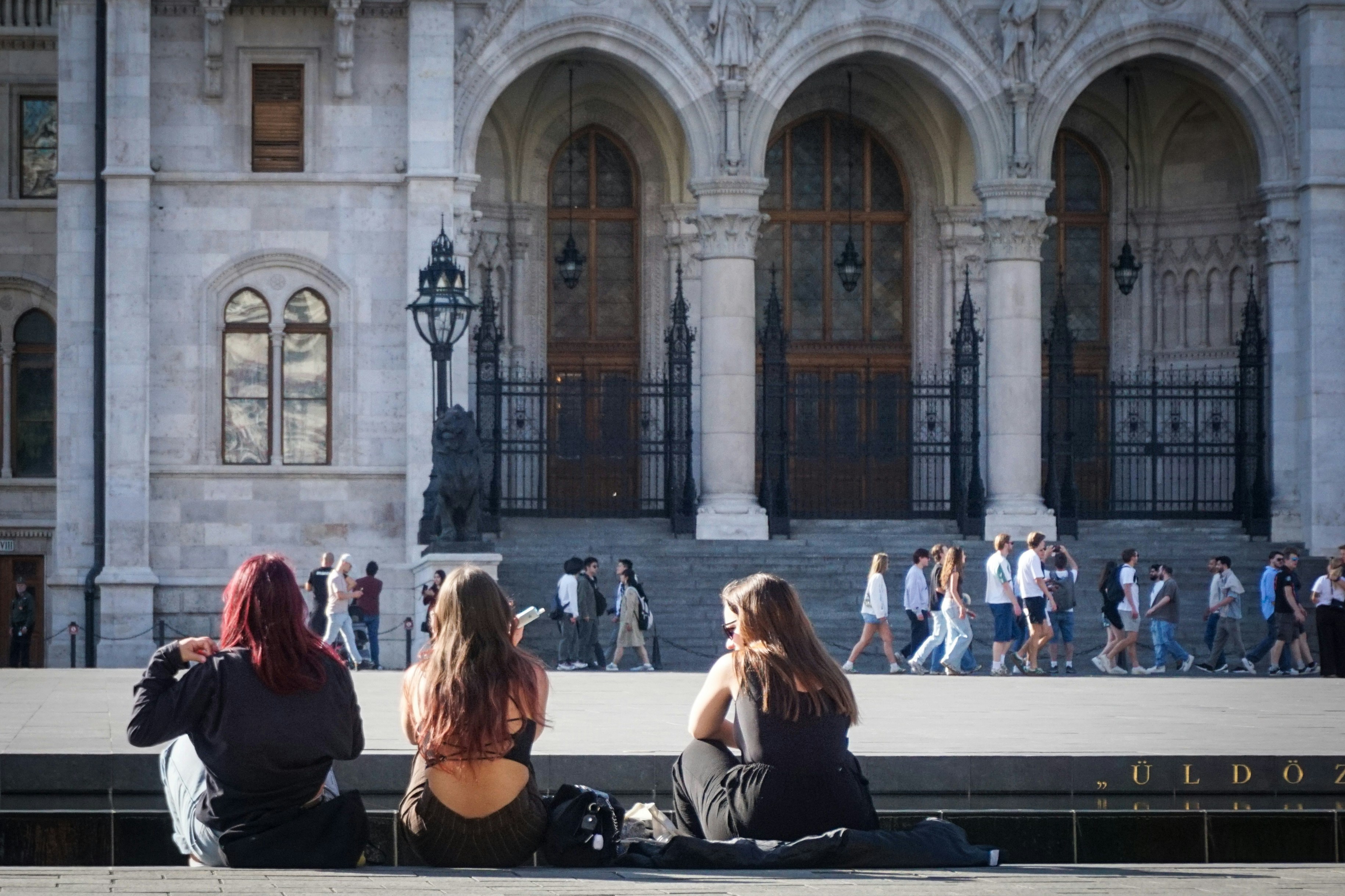 Three friends in the foreground overlook a grand neoclassical facade