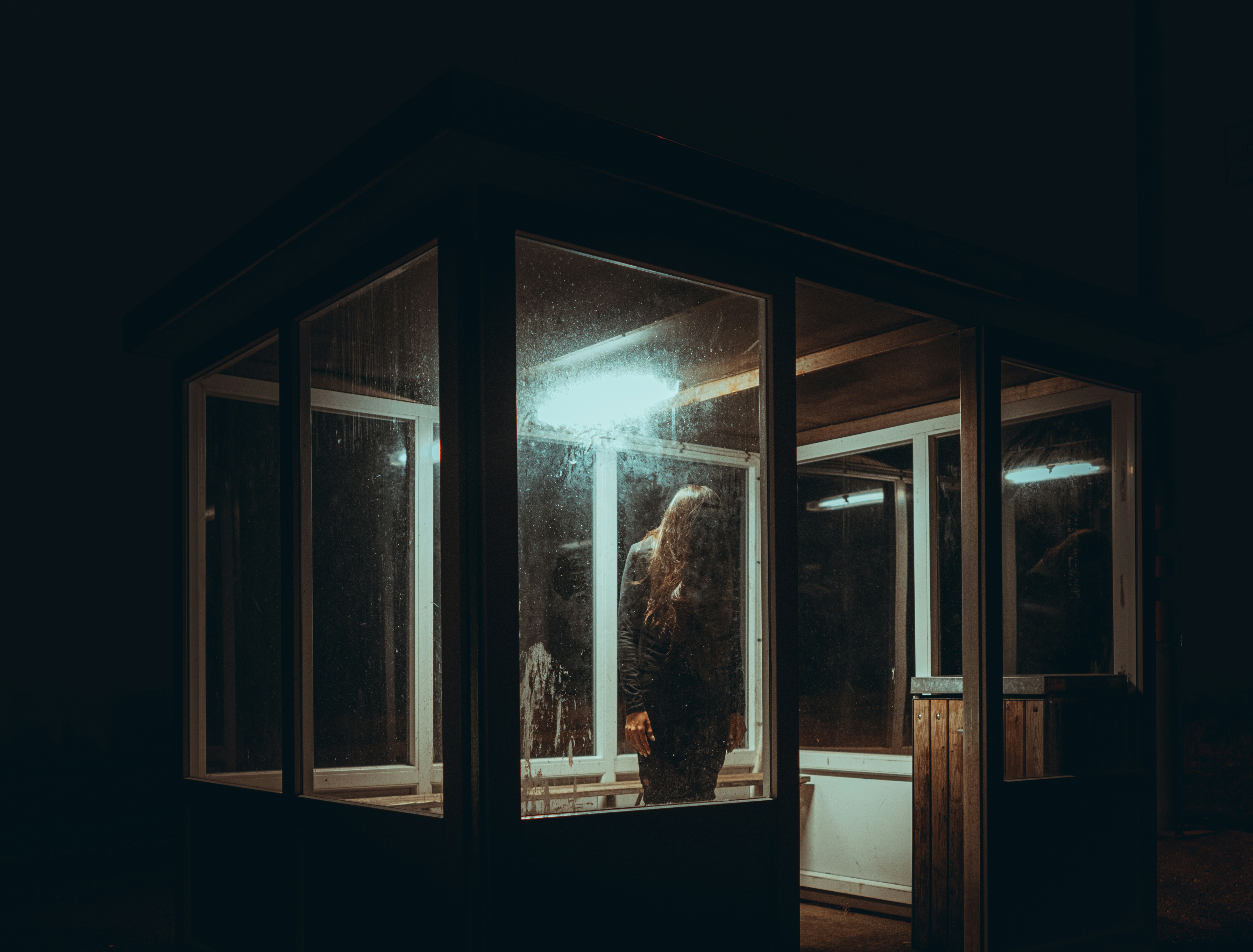 Night Surveillance Booth: A Quiet Figure in Glass and Neon
