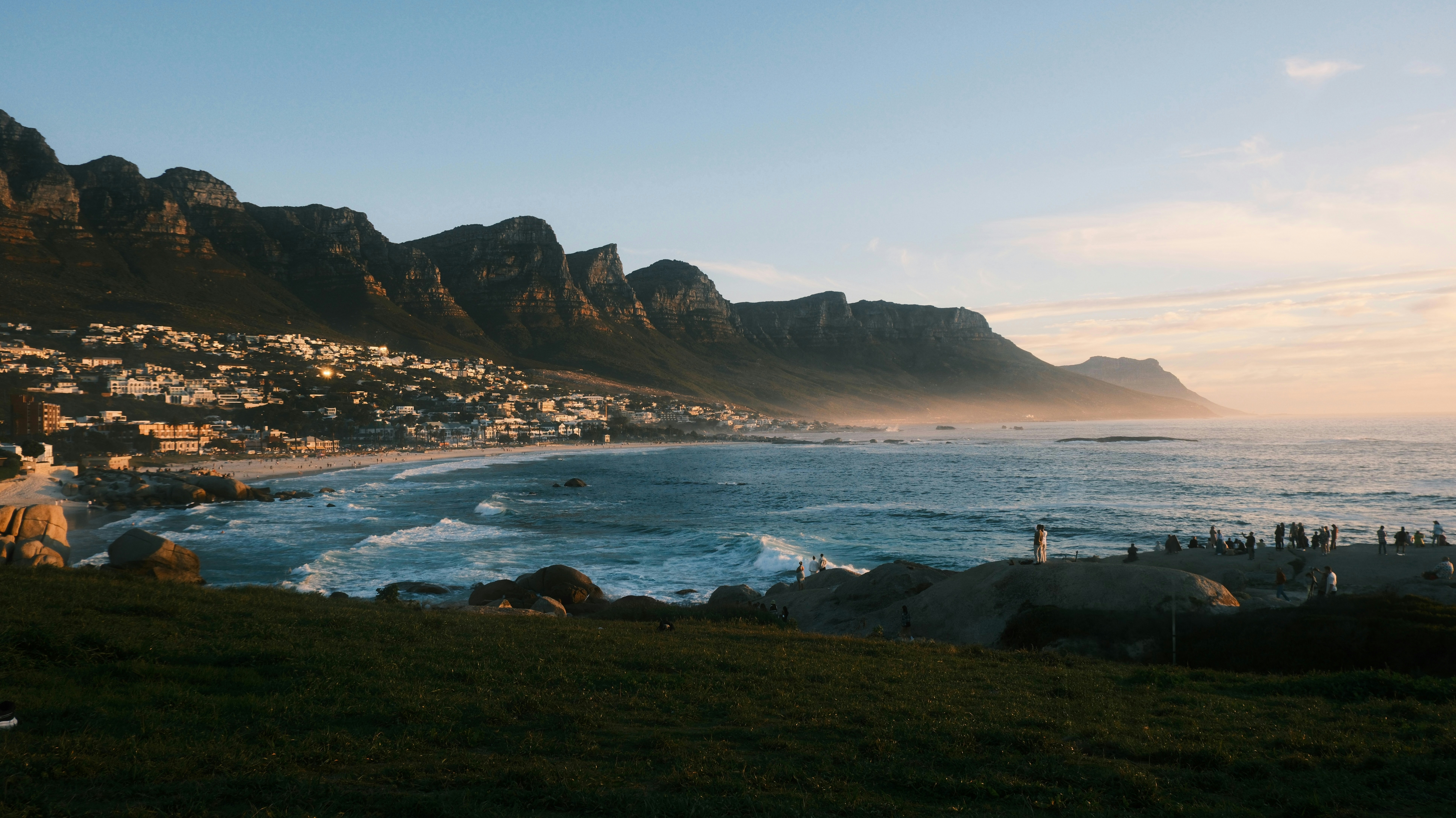 Coastal town beneath rugged cliffs at golden hour
