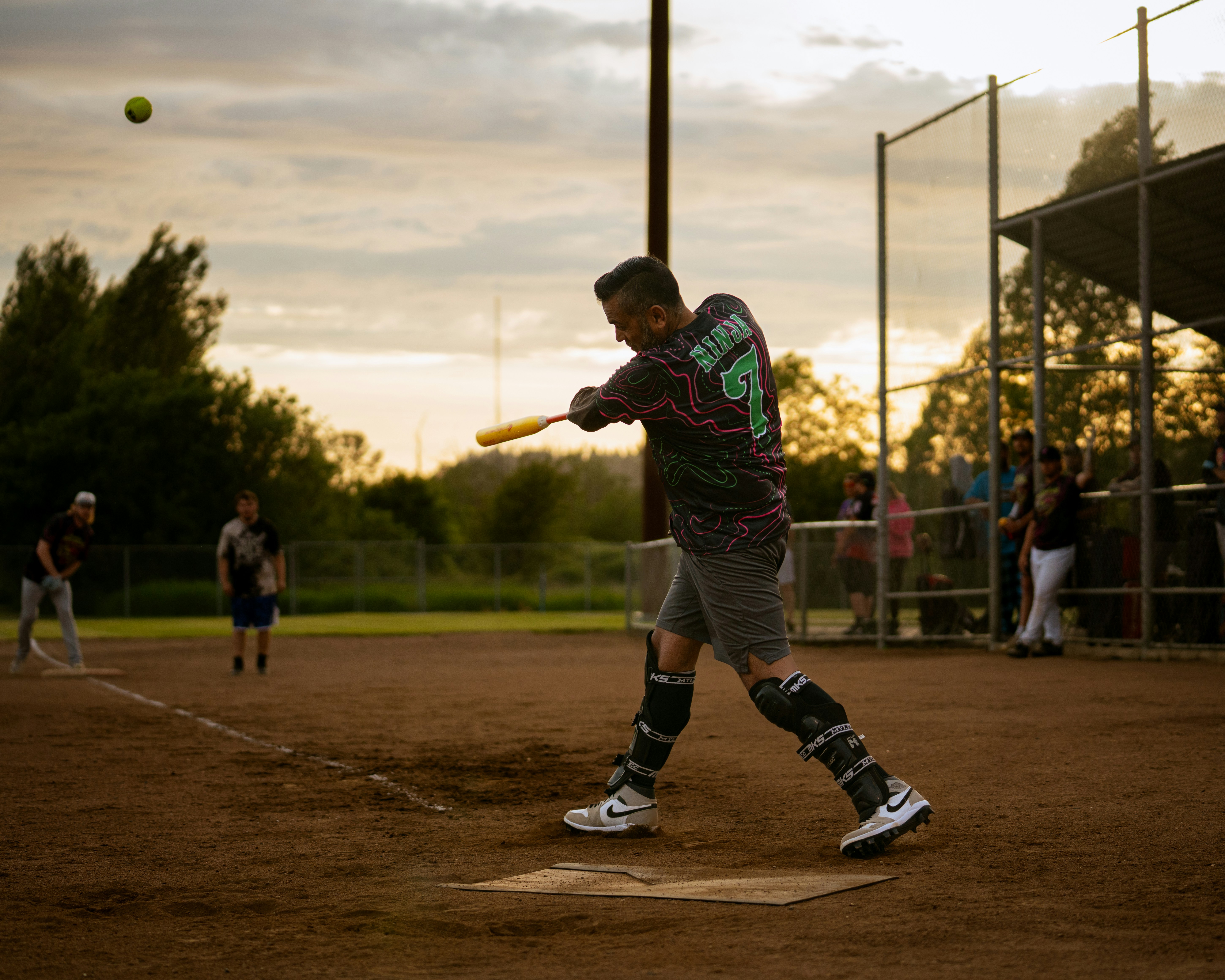 Swing at Dusk: The Batter Connects with a Blazing Evening Pitch