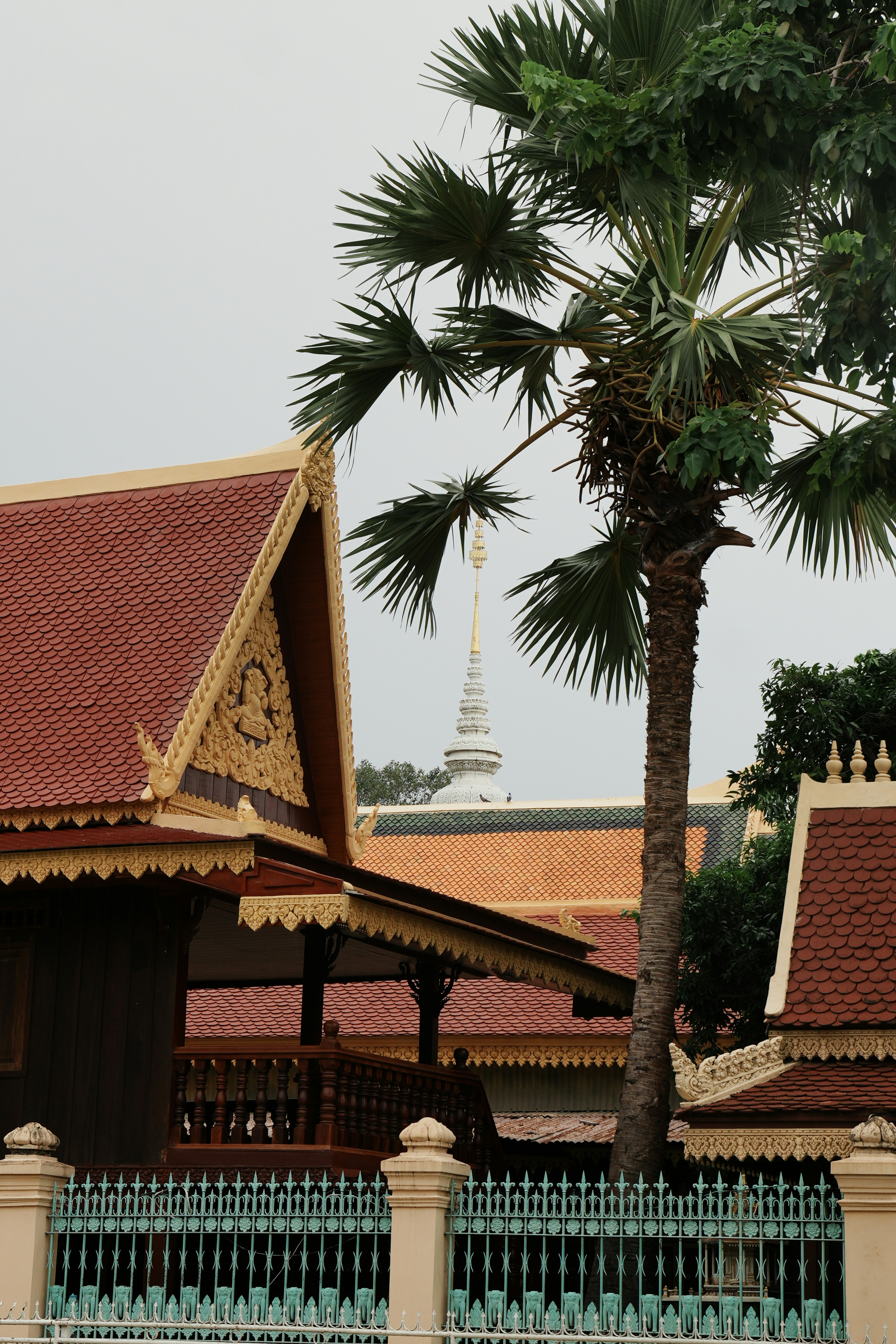 Ornate Thai Temple Rooflines Framed by Palm and Spire