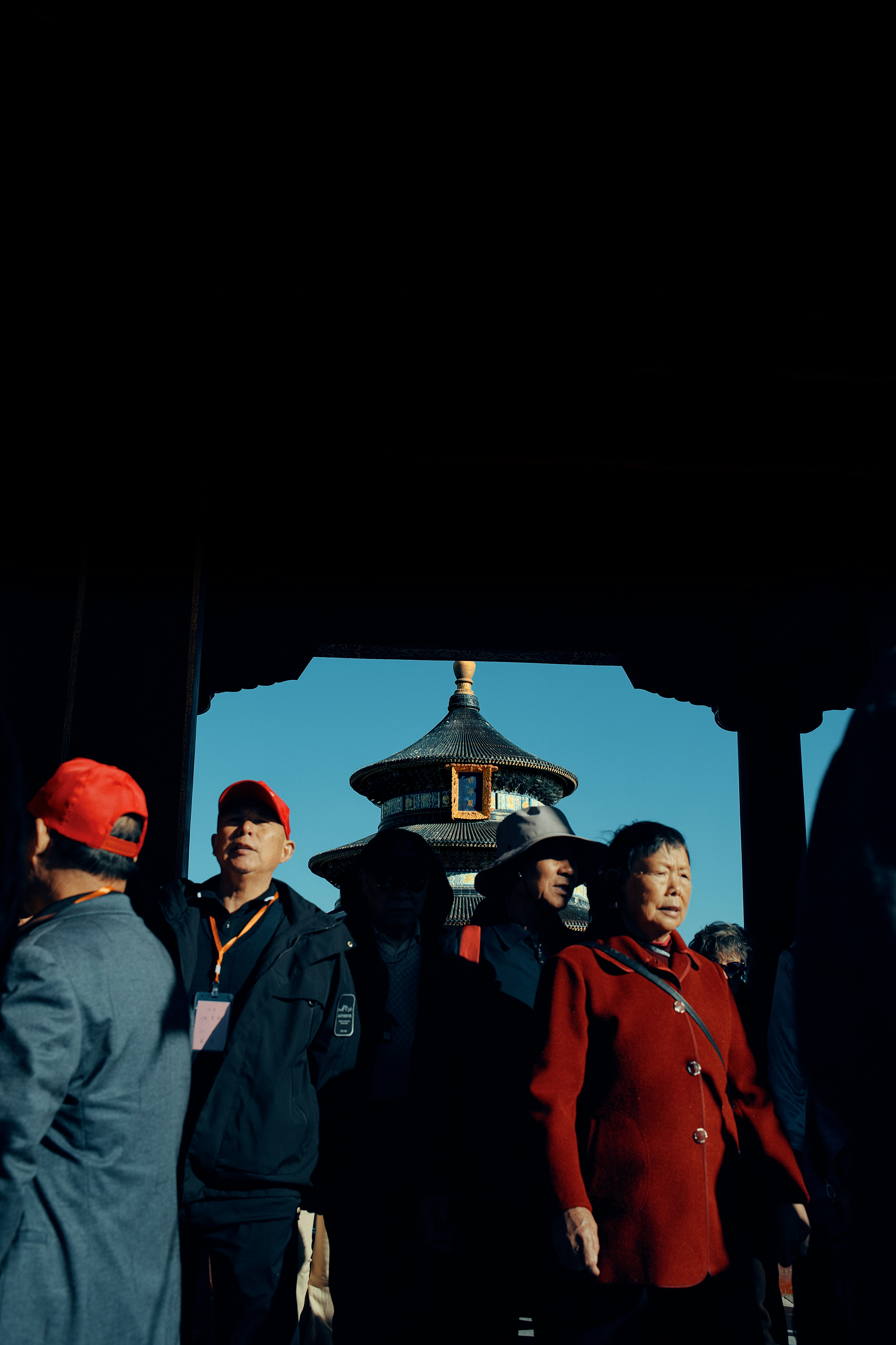 Red-clad figure framed by temple roof at a bustling courtyard