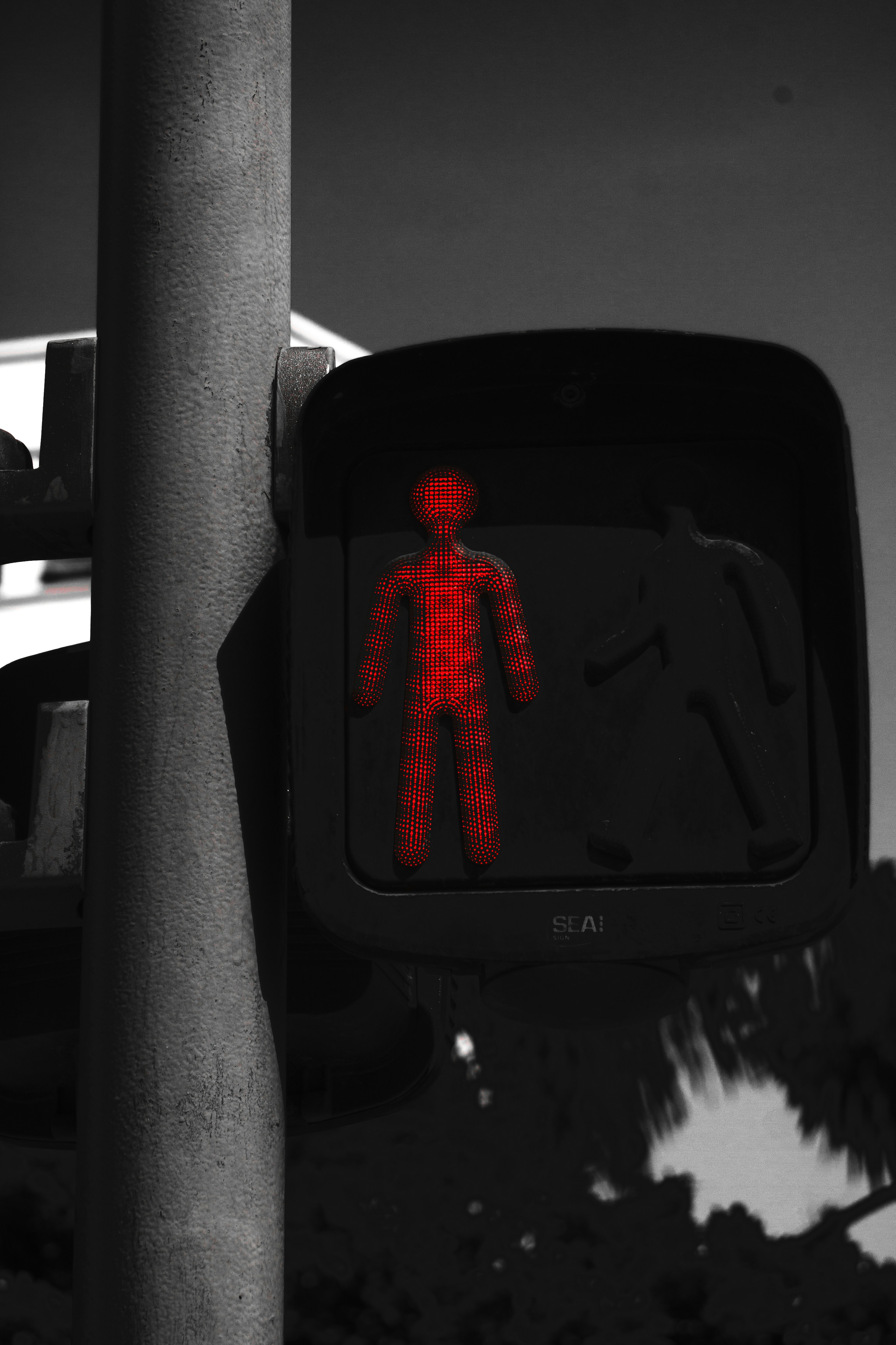 Red pedestrian signal emerging from the urban shadow