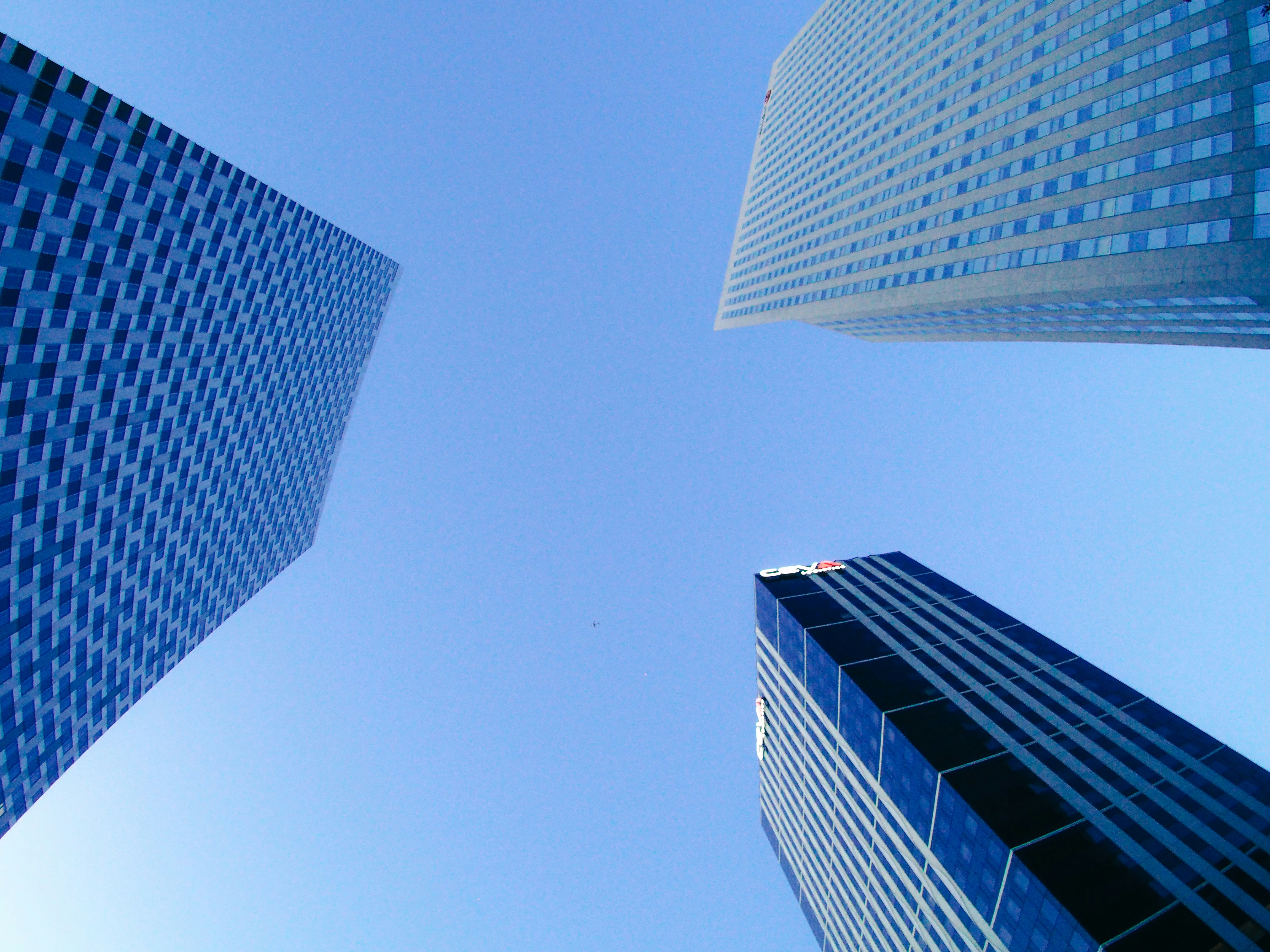 Skyward Confluence: Glass Towers Meeting in Clear Daylight