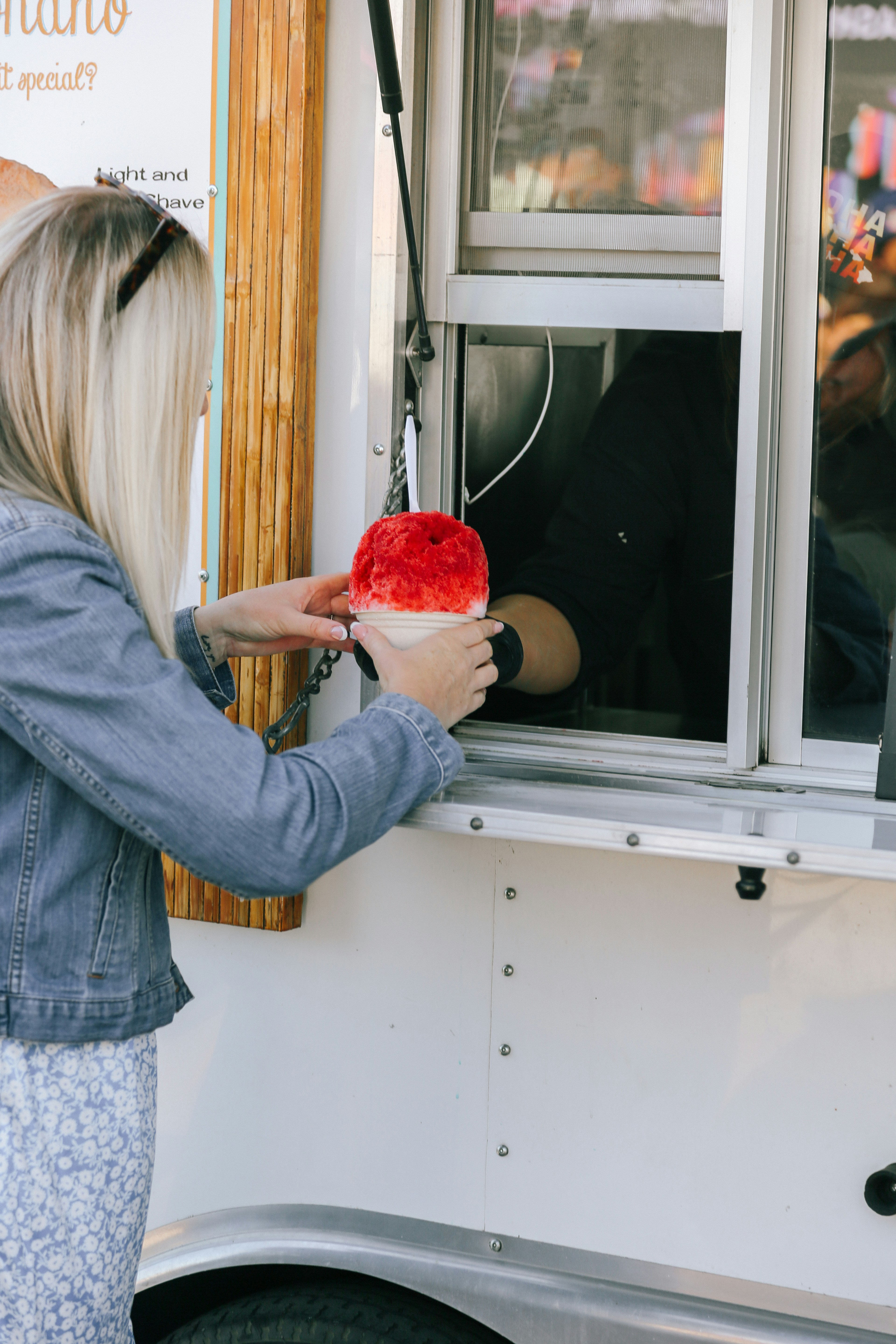Handing off a bright red shaved ice through a service window
