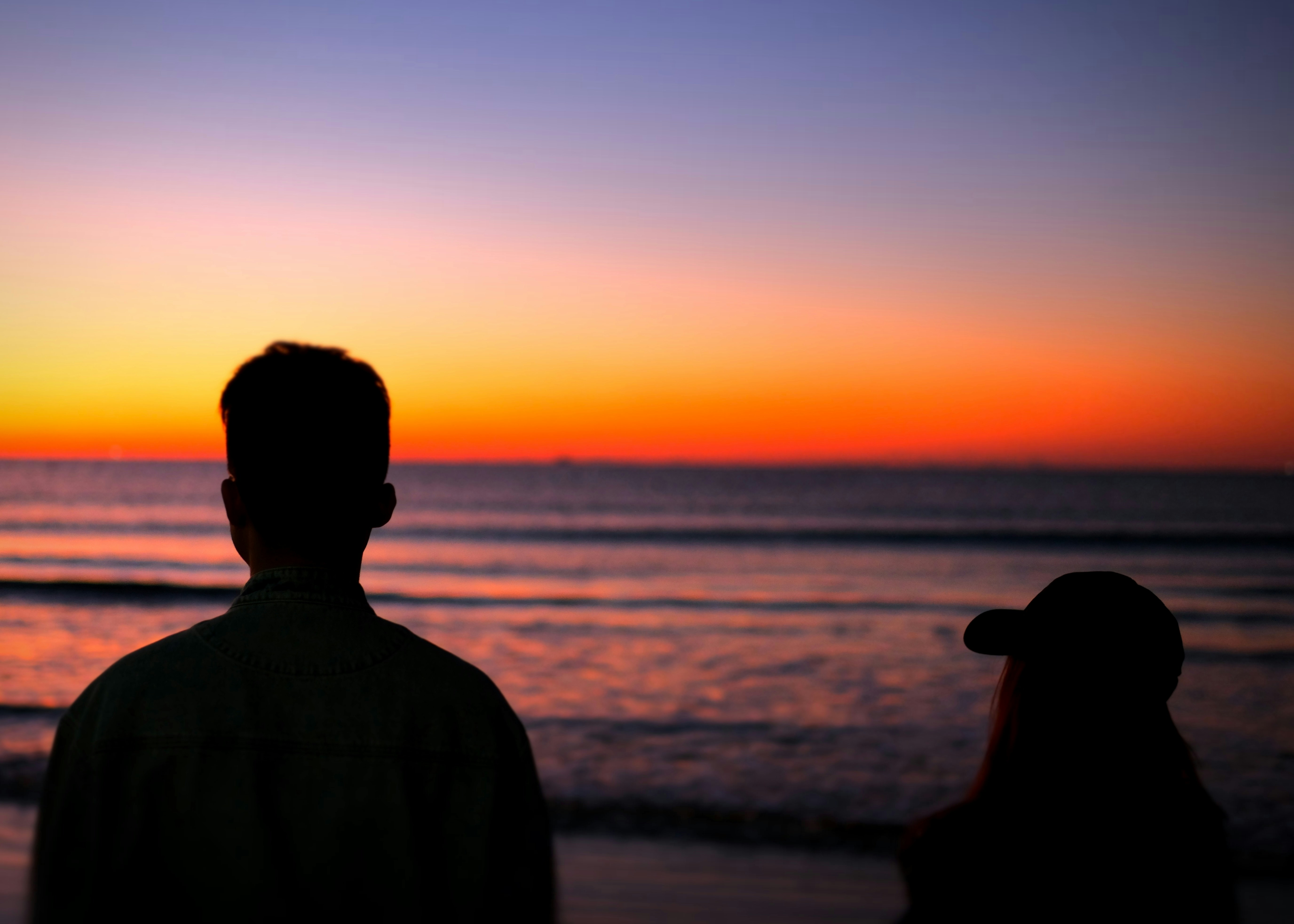 Silhouetted Companions Against a Sunset at the Shore