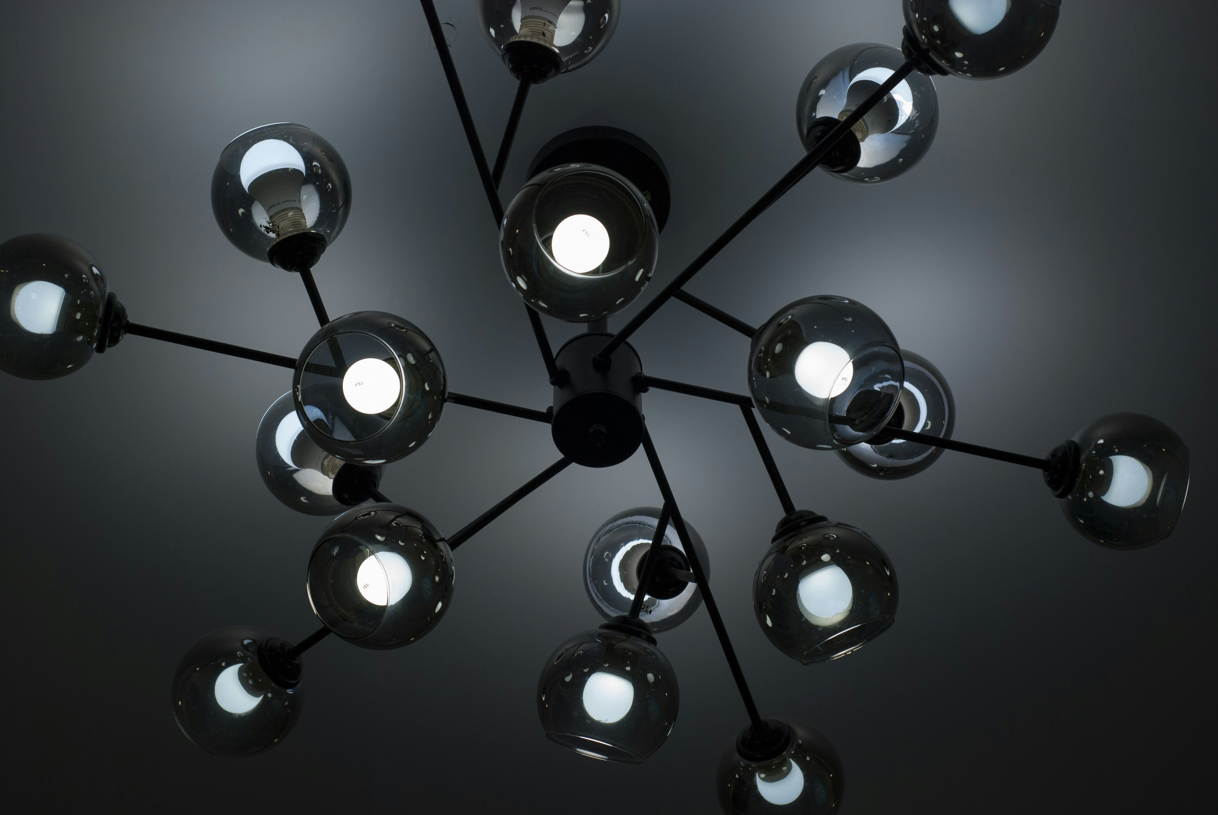 Glass orbs connected by dark rods form a radial fixture with bright centers, creating an abstract chandelier-like composition.