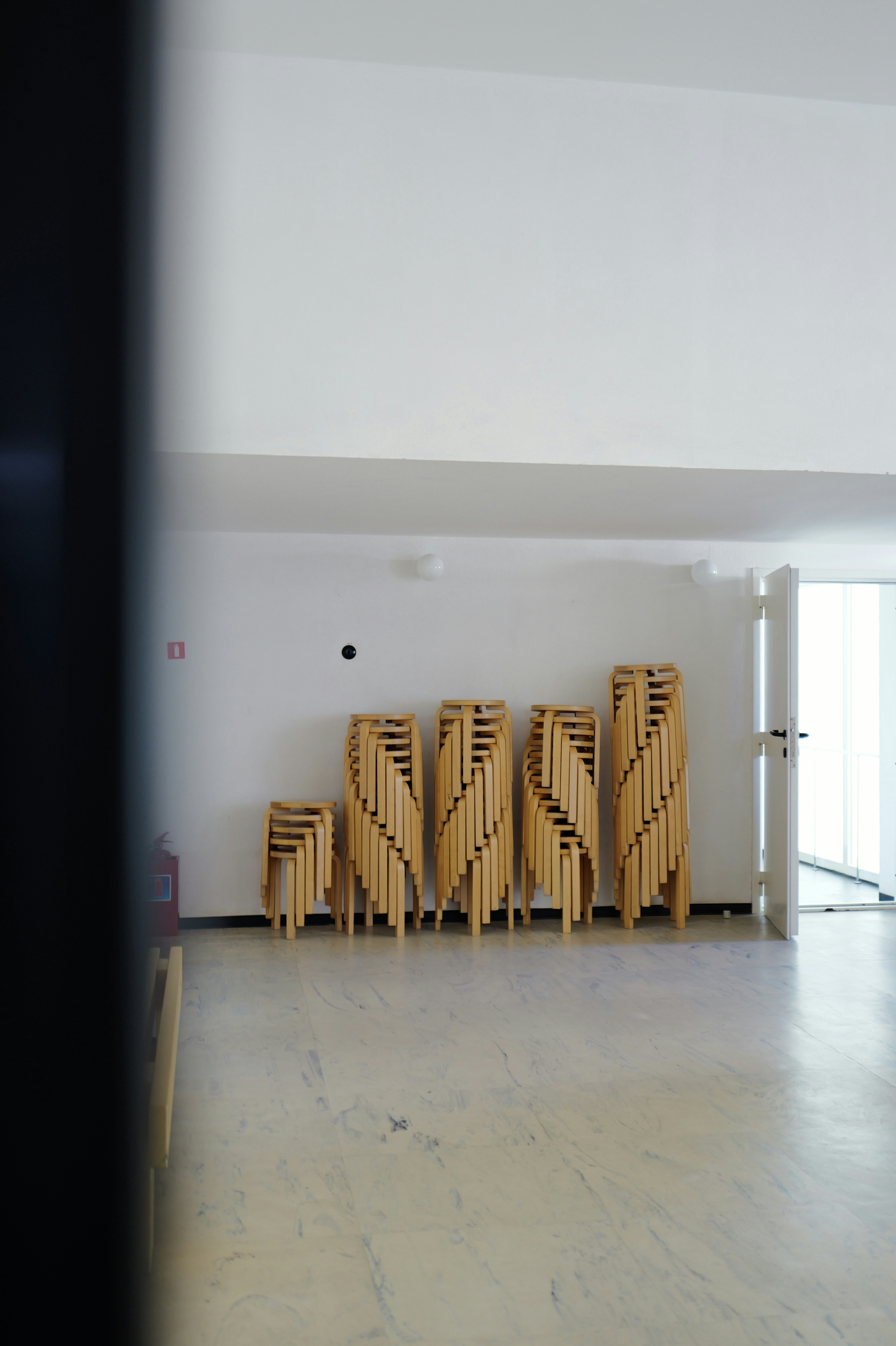 Stacked Wooden Chairs in a Quiet Corridor