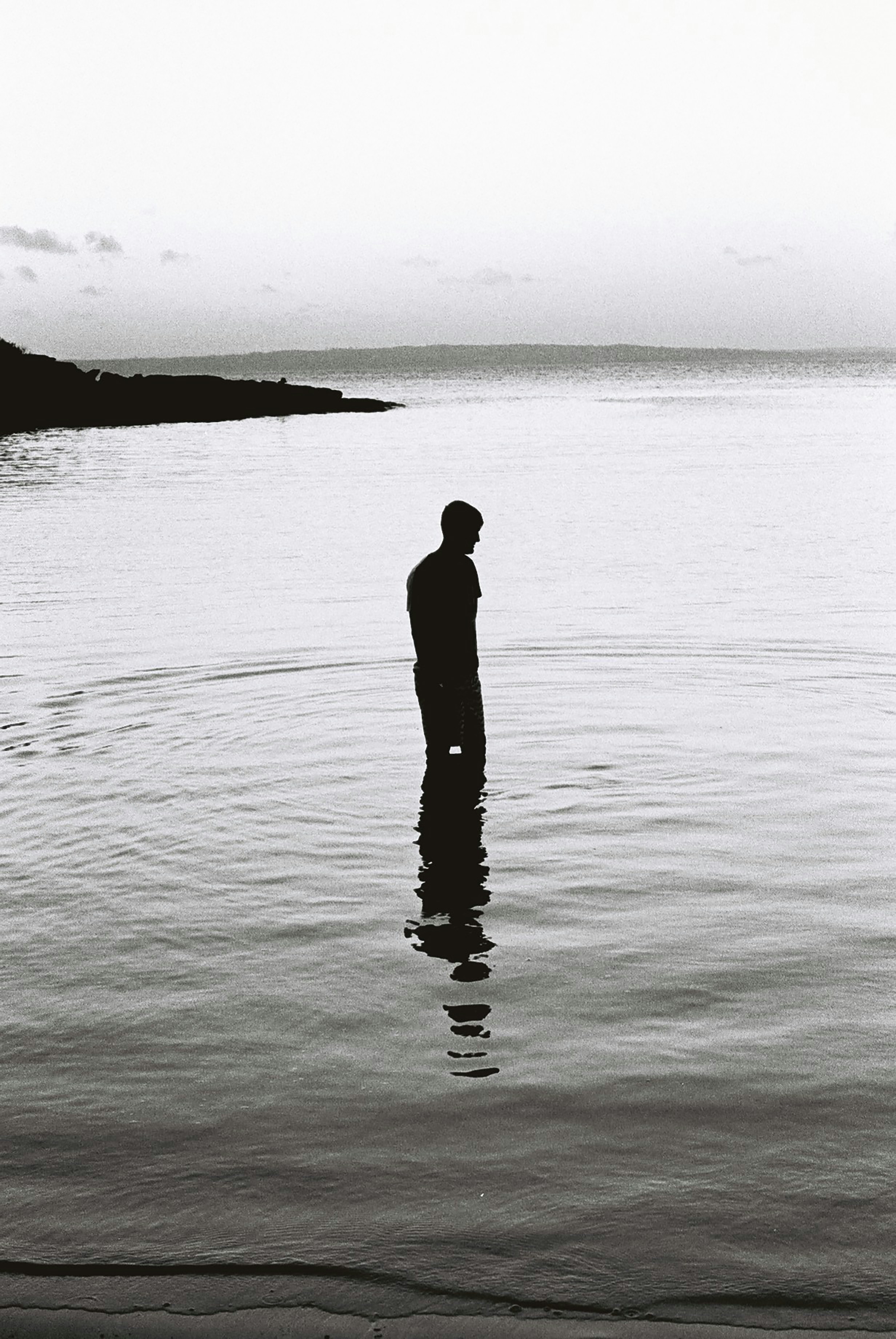 Silhouette in Quiet Tide: A Lone Figure Standing in Tidal Stillness