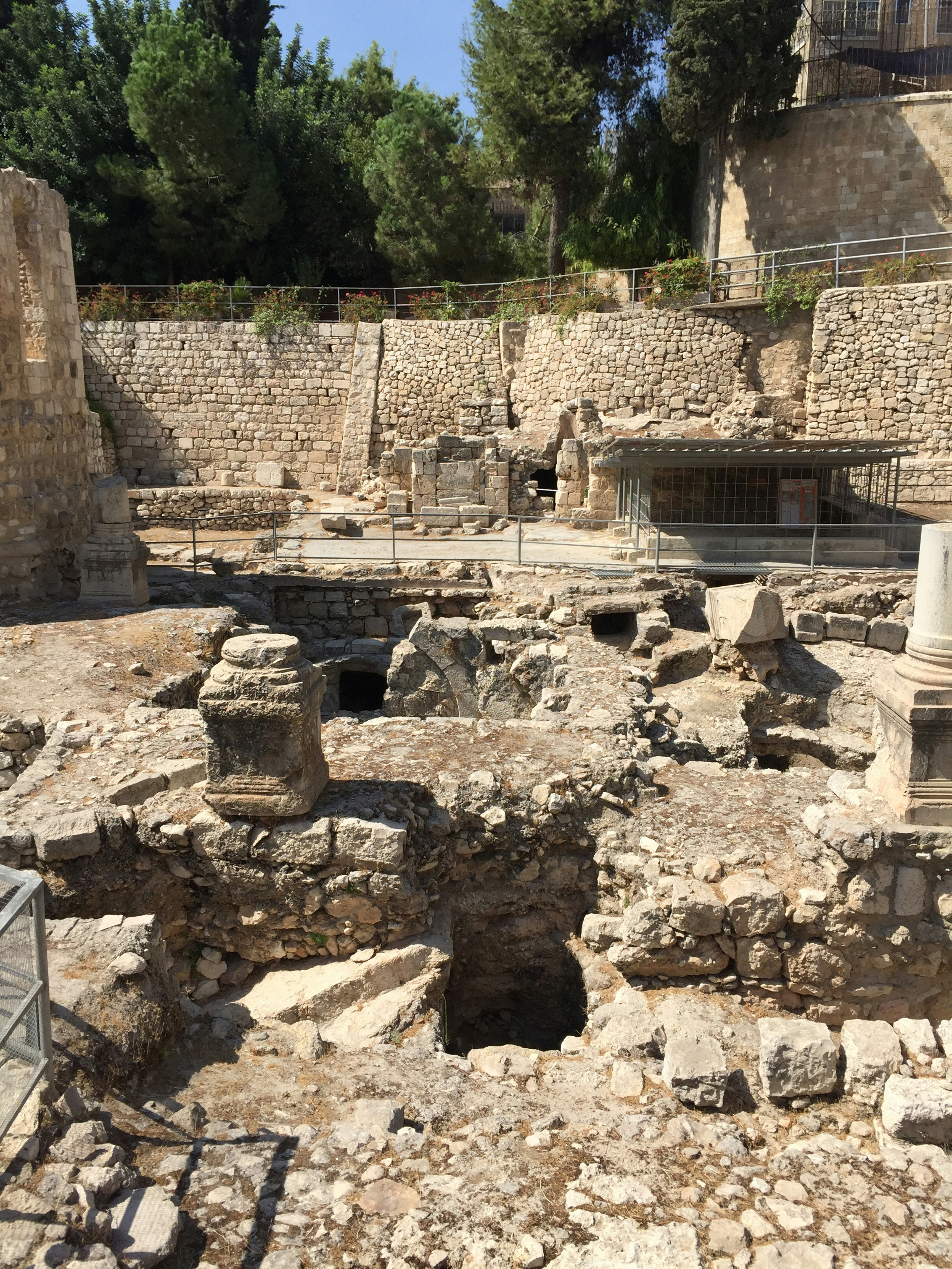 Sunlit ruins with stacked stone walls and ancient steps, exposing a weathered archaeological site.