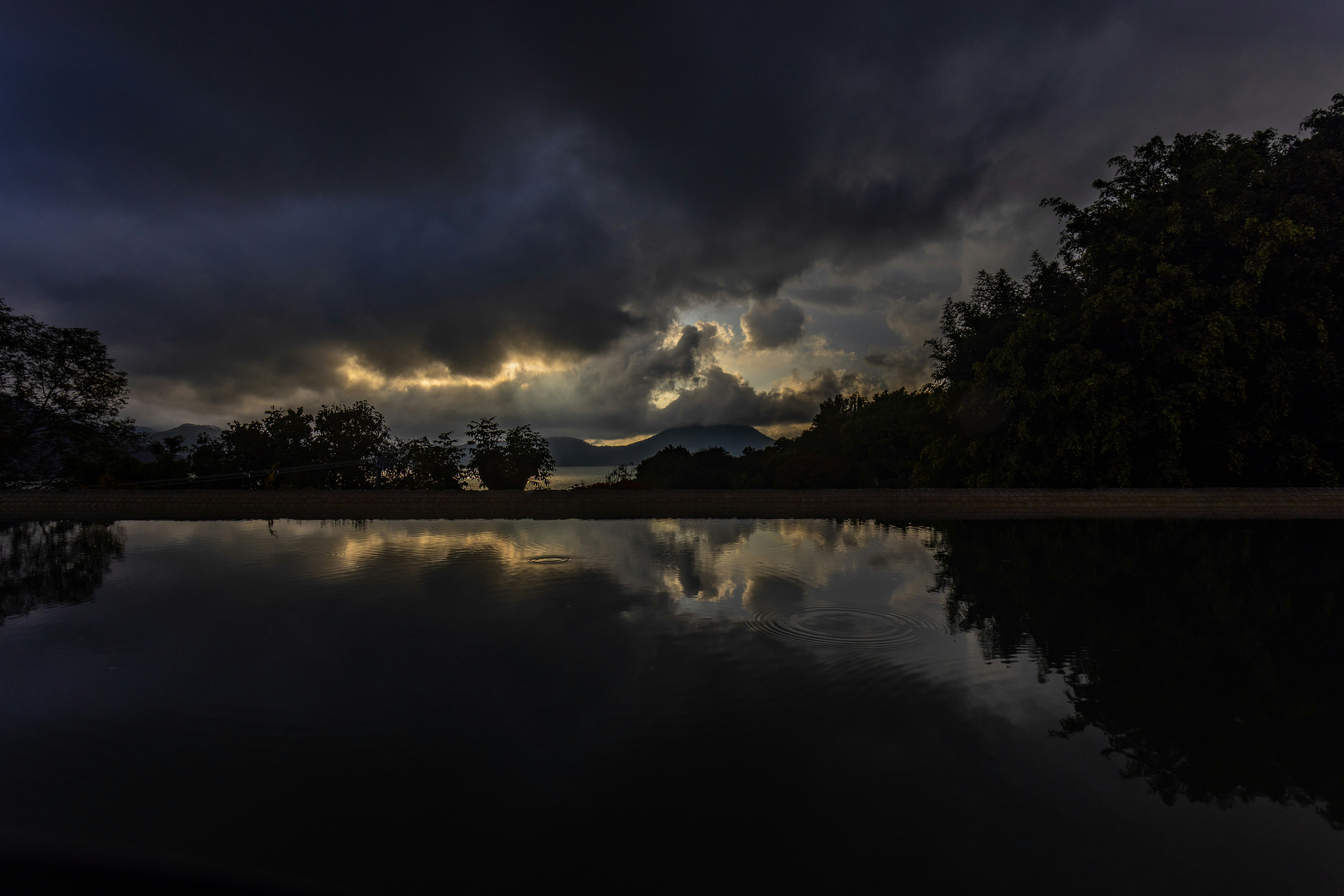 Dark horizon at dusk: clouds echoing across still water