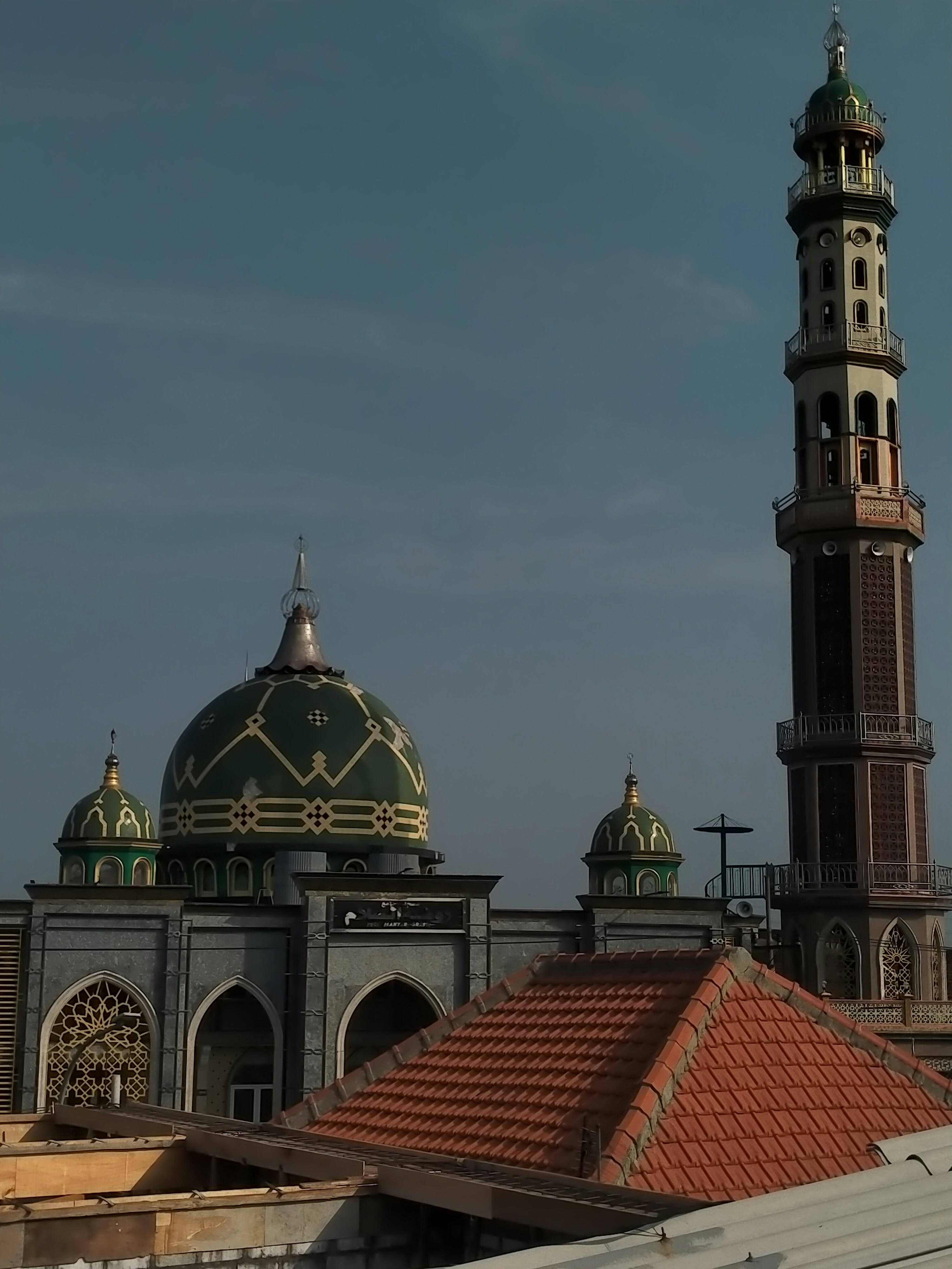 Islamic skyline: emerald domes and a towering minaret against a clear blue sky