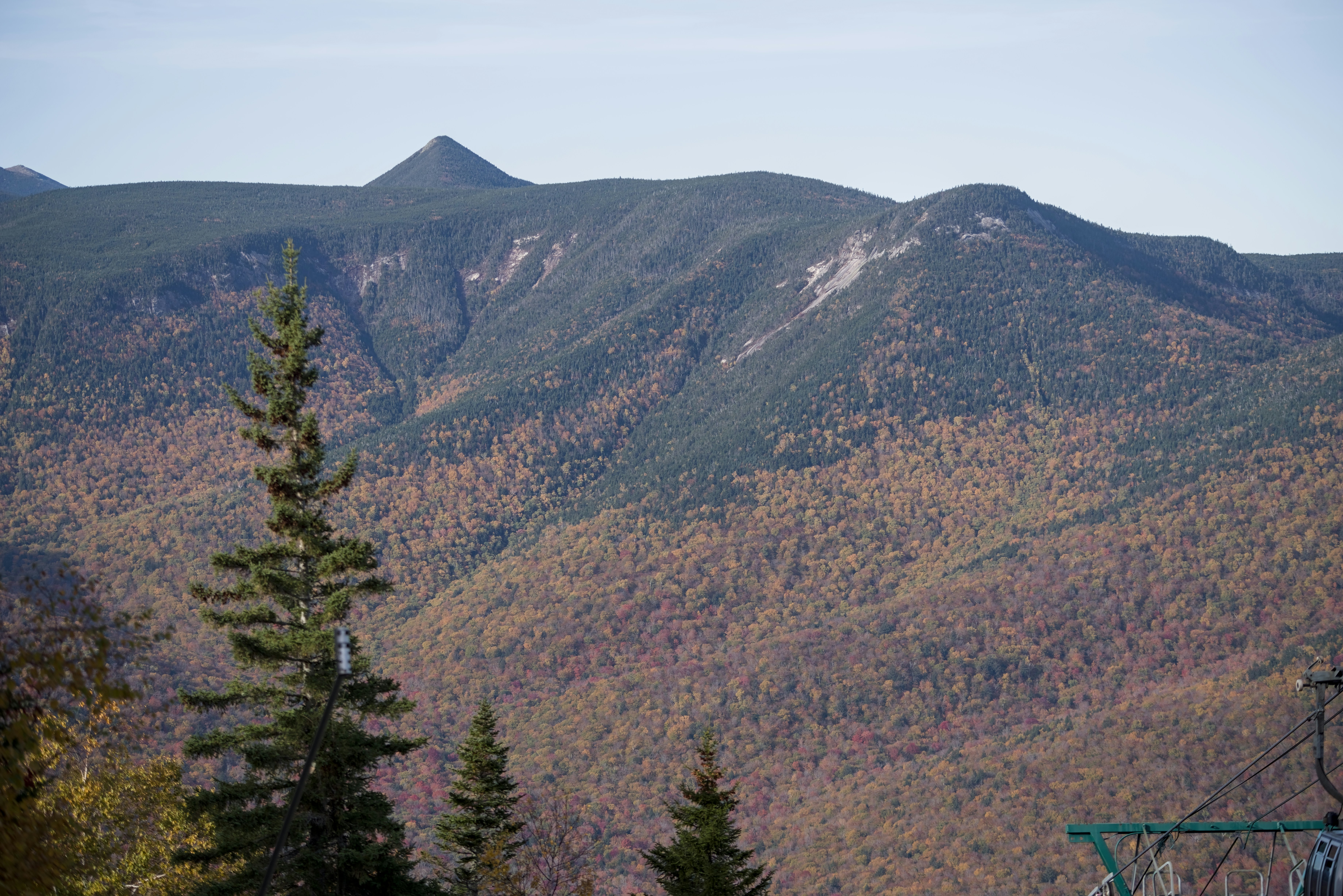 Autumnal mountain ridge with evergreen foregrounds and a clear blue sky, capturing the hillside forest color transition; a landscape photograph likely for natural scenery or park documentation.