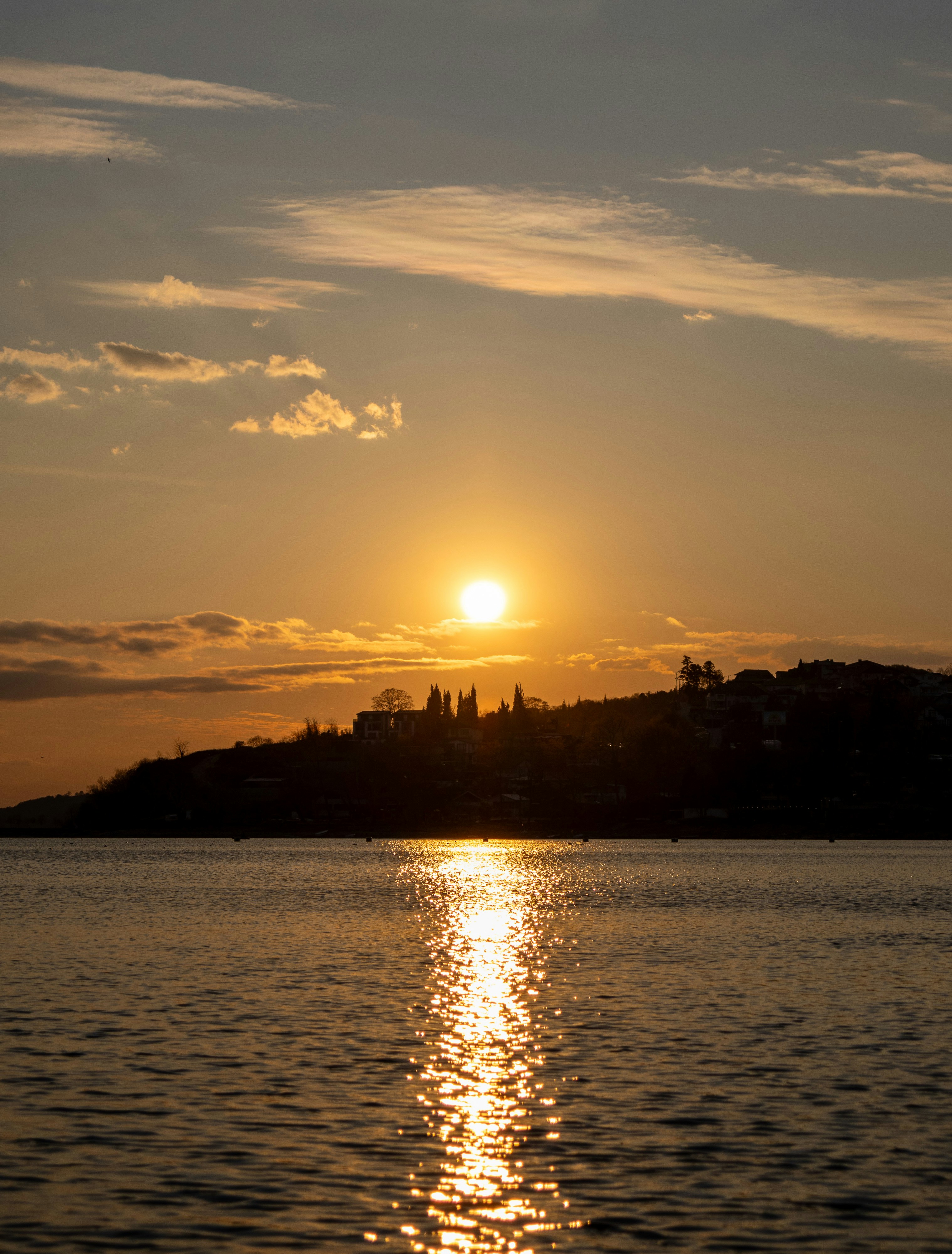 Sunlit Crest: Sunset Over Silhouetted Hills and Glimmering Tides