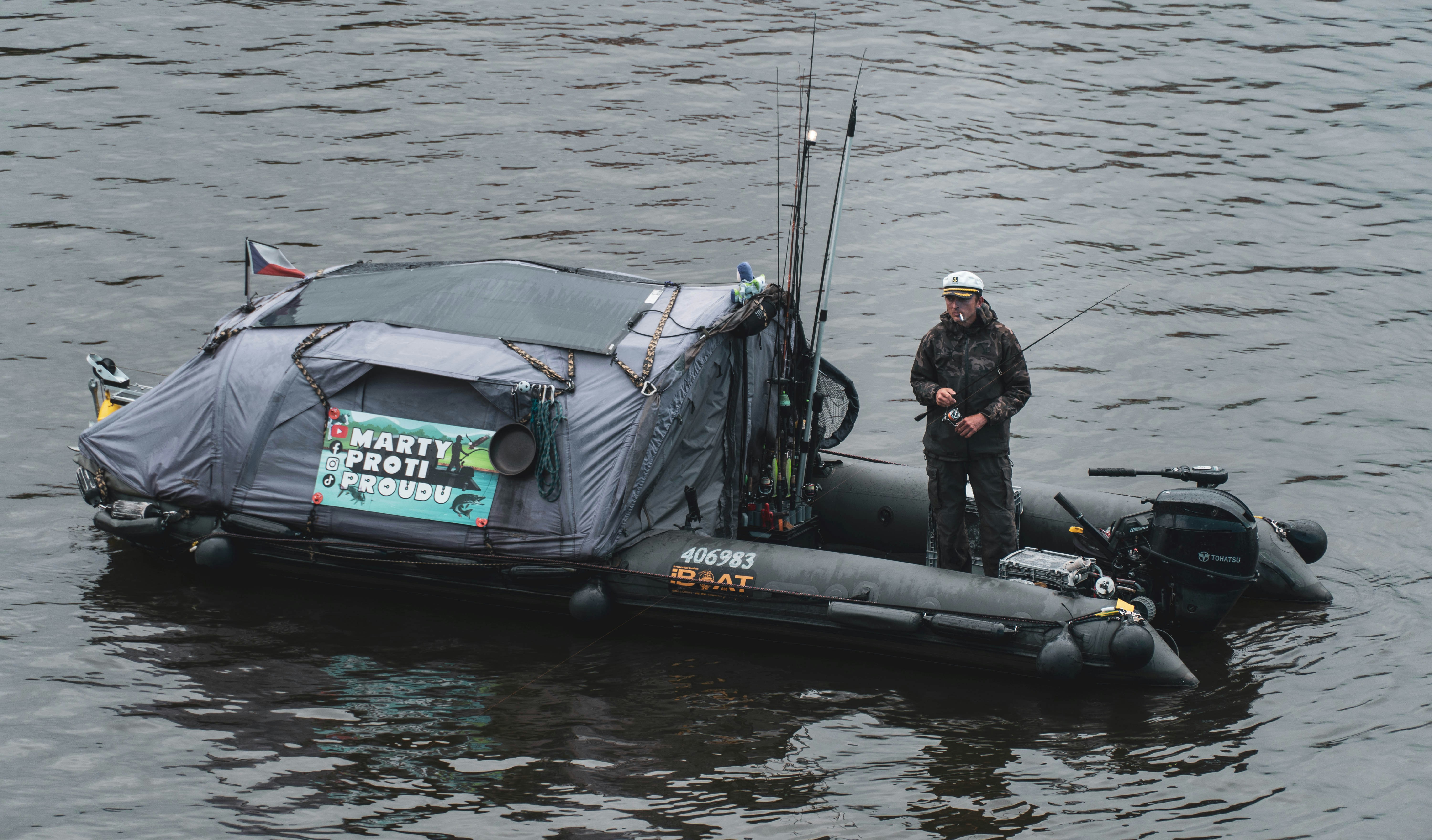 Floating Shelter: A rugged inflatable craft moored with a lone observer on a choppy river