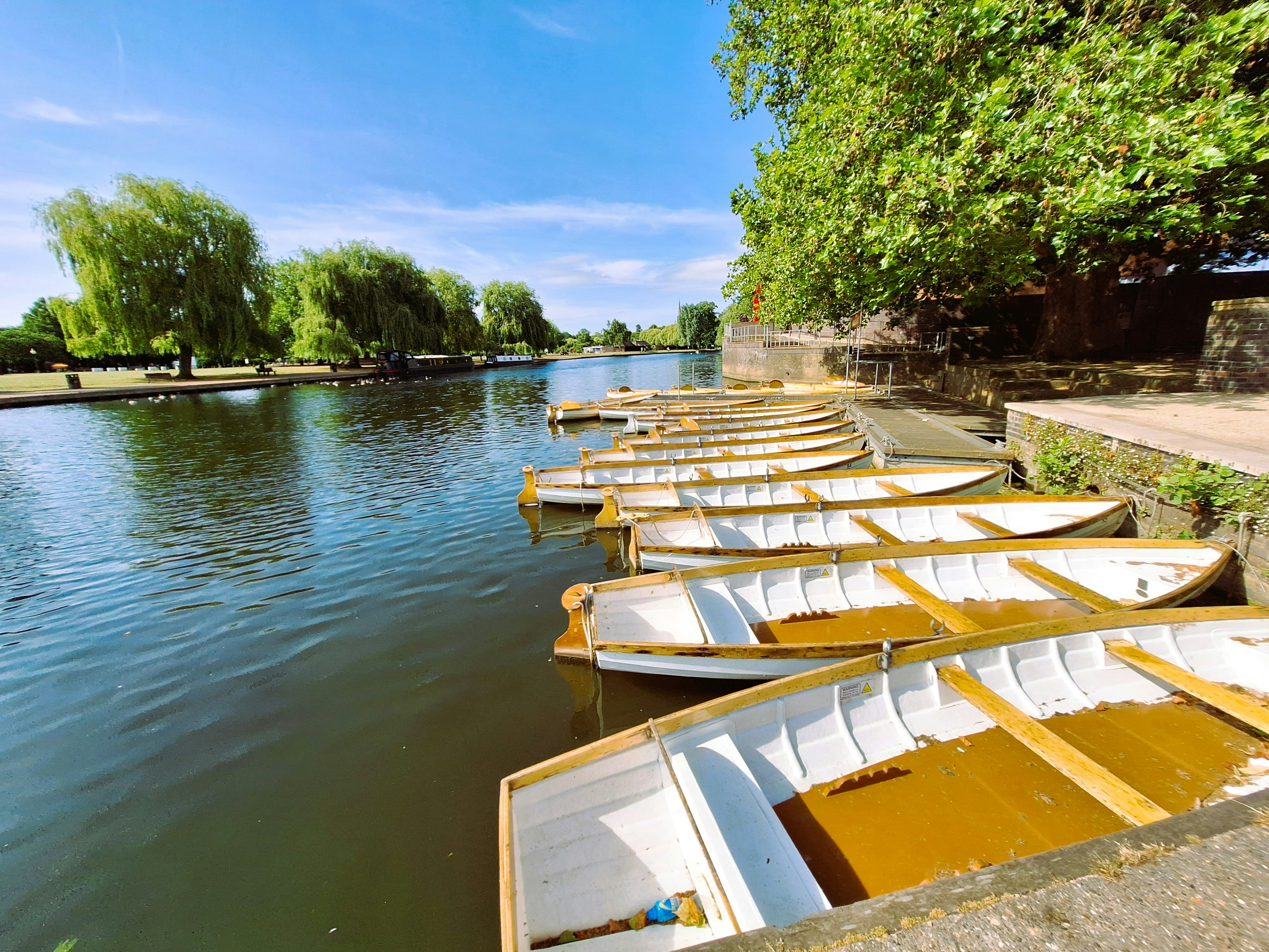 Row of sunlit boats along a tranquil riverside quay