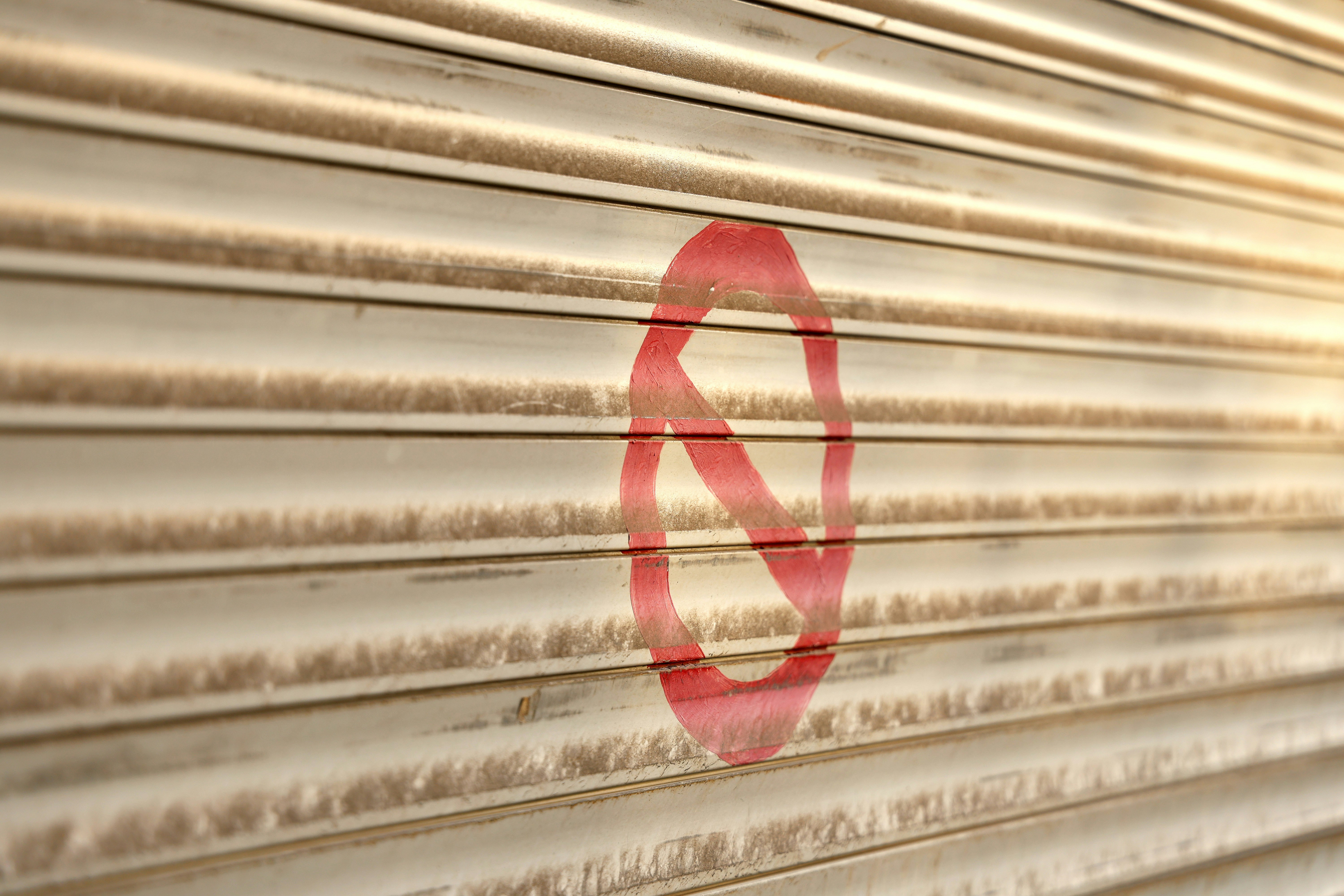 Red Zone: Weathered No-Parking Symbol on a Rusted Metal Gate