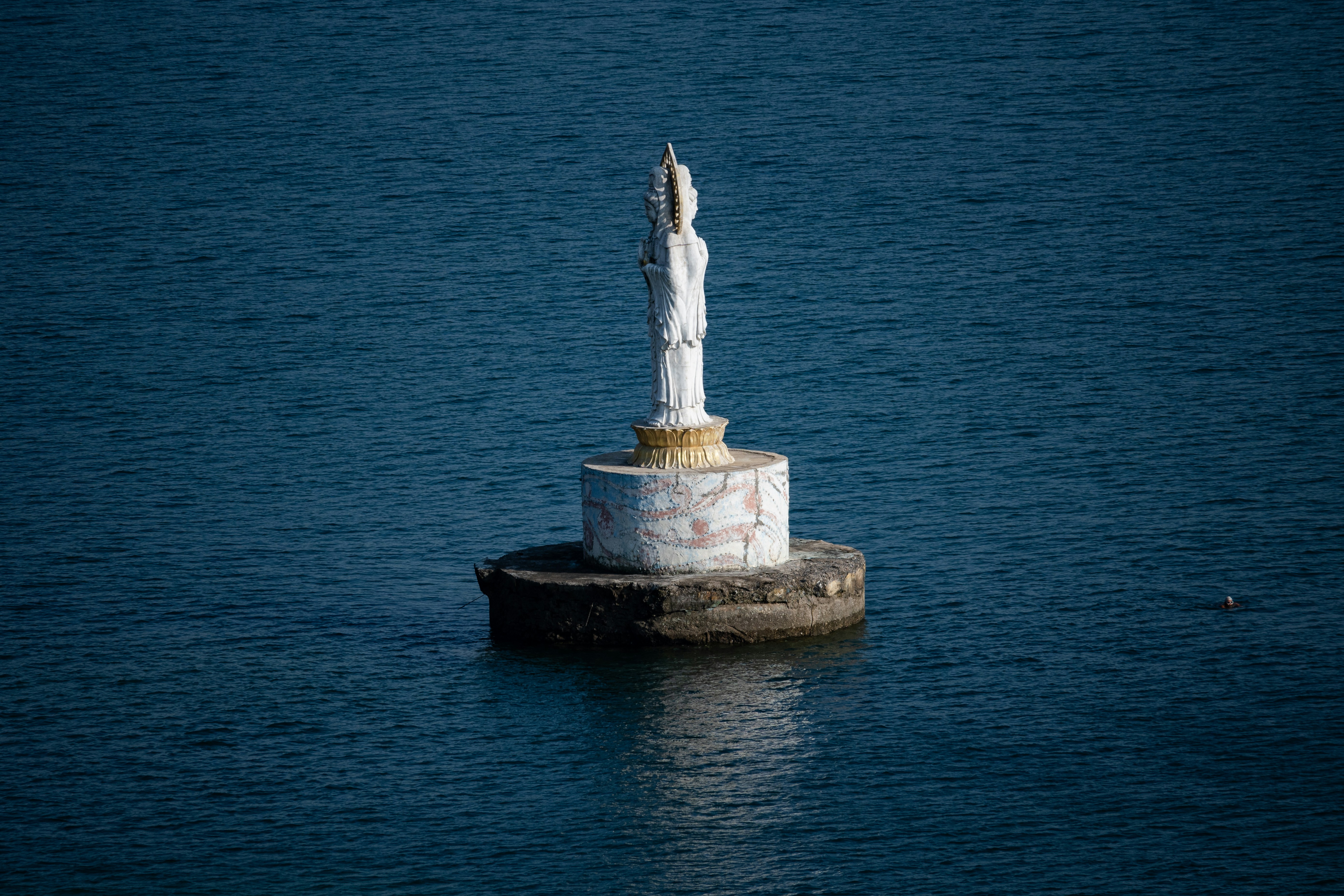 Statue on a Plinth Rising from a Calm Blue Sea