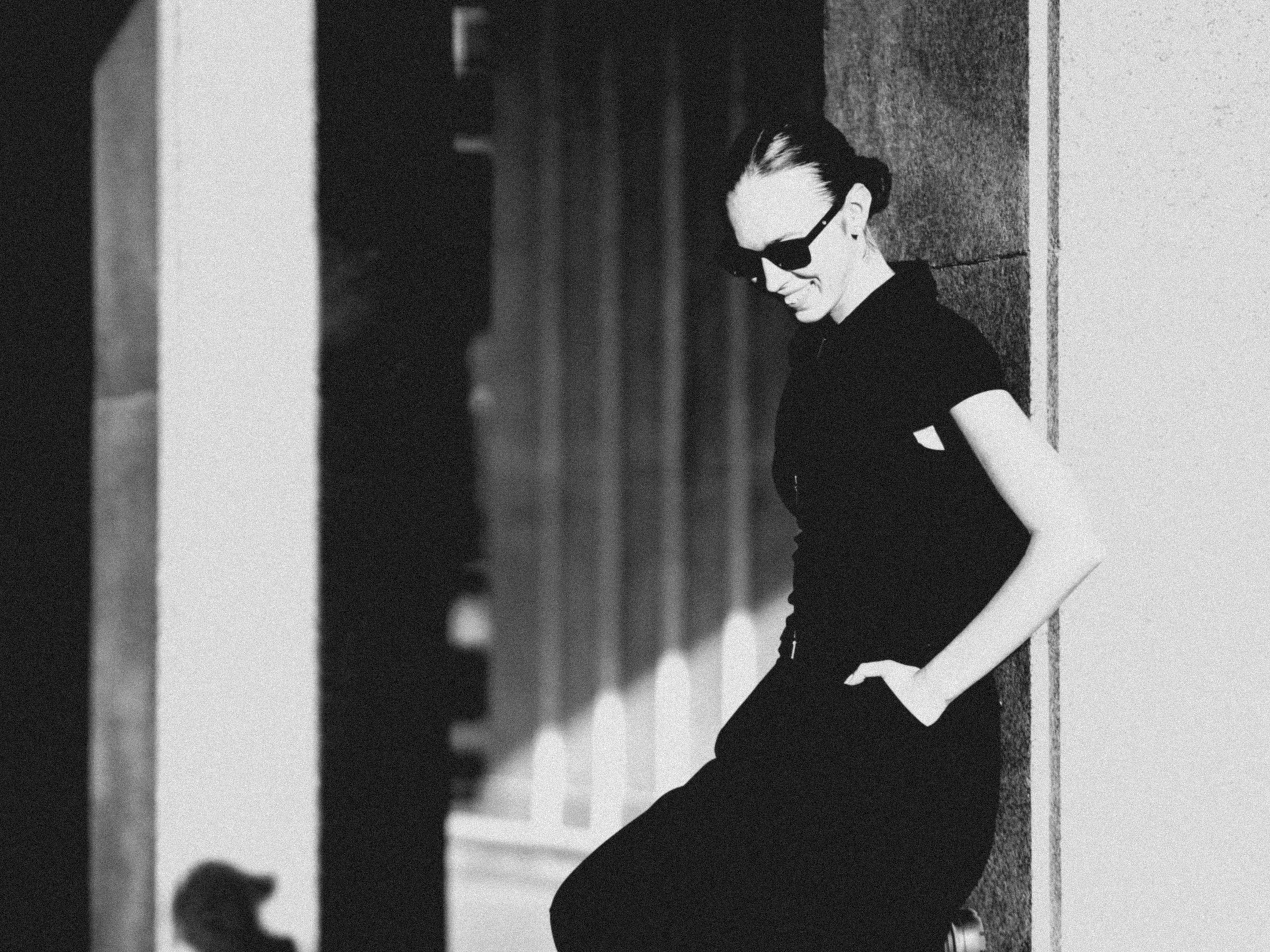 Shadowed Grace: A Woman in Motion by a Sunlit Wall