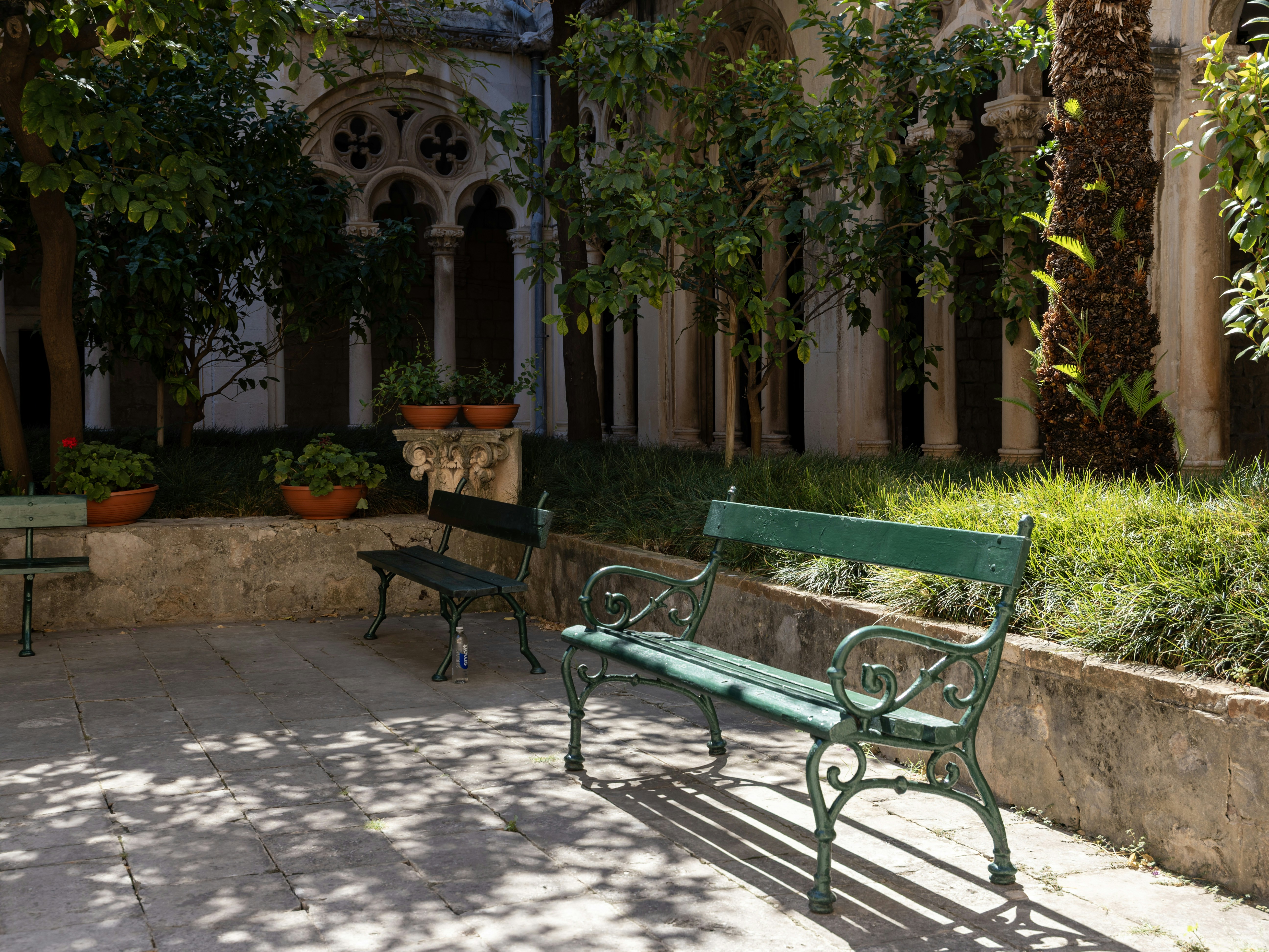 Green Cast Iron Bench in Sunlit Cloister Garden