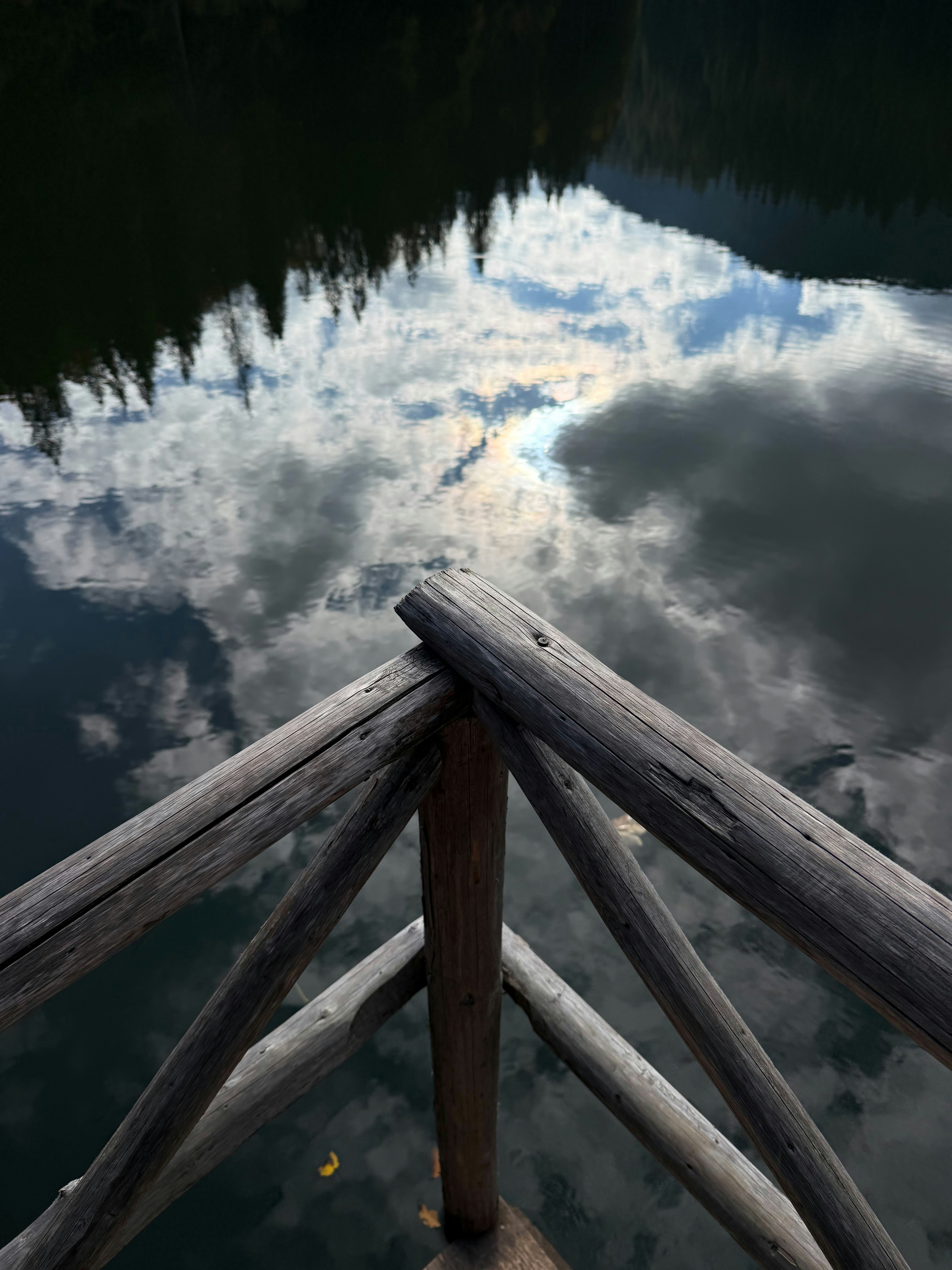 Wooden railing folds into a mirrored lake horizon