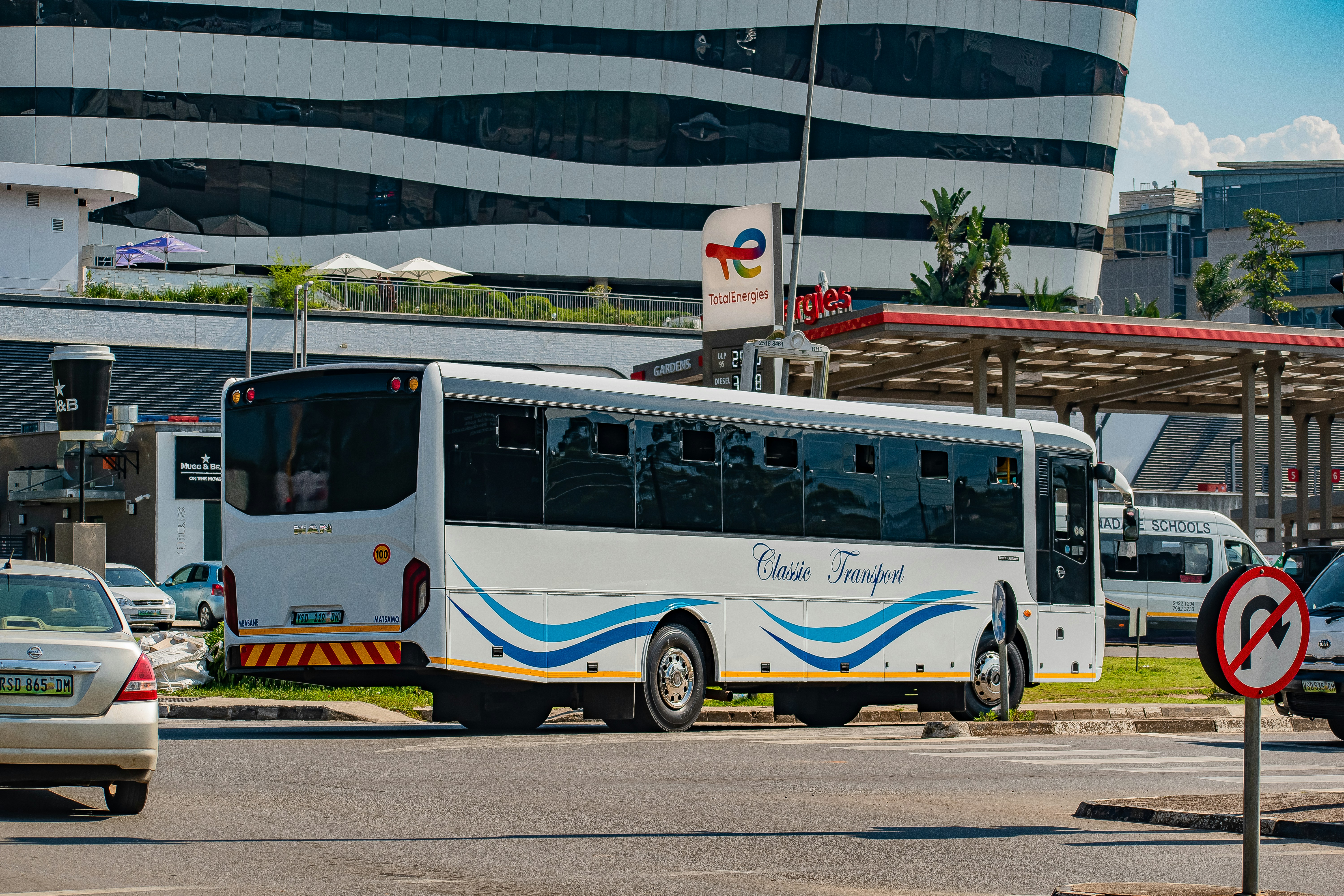Blue Wave Coach: A City Bus Crossing Under Modern Architecture