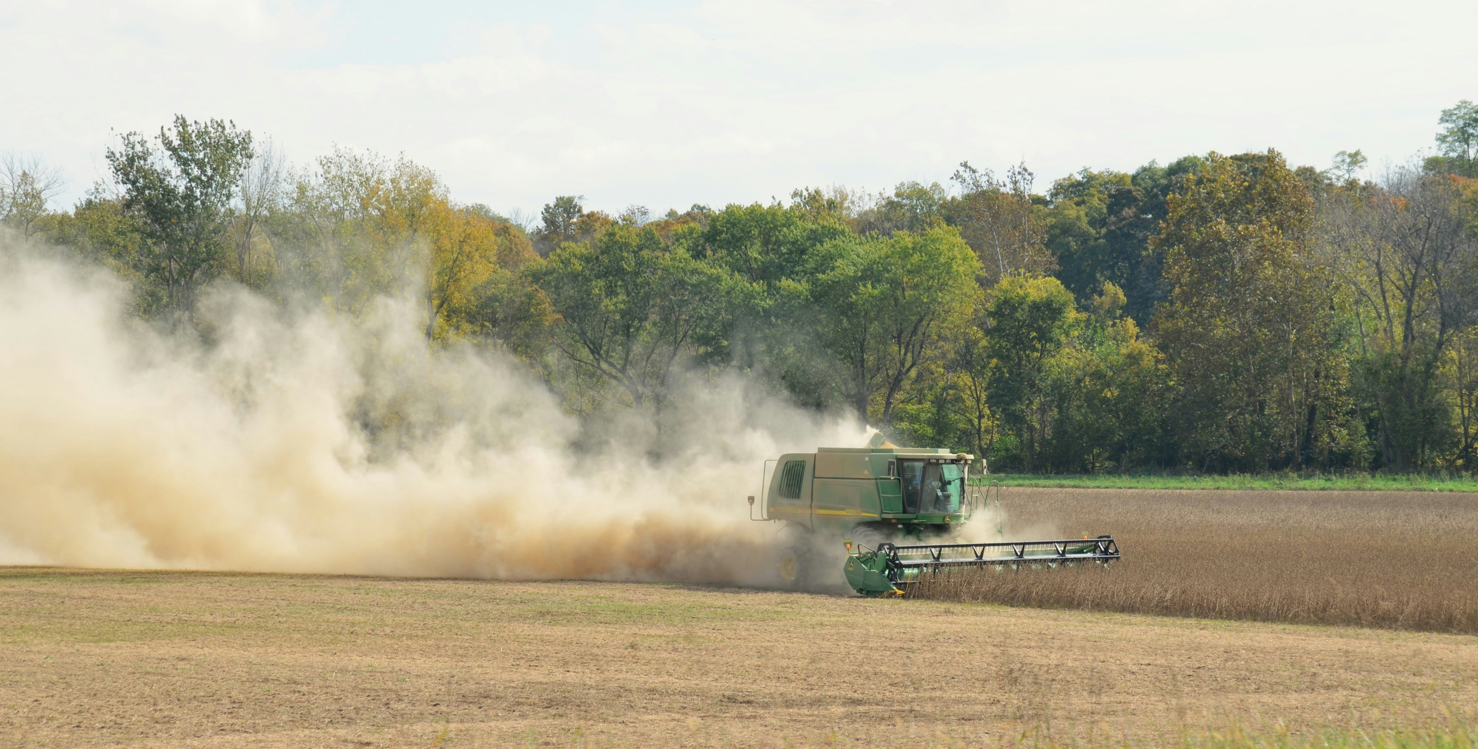 Dusty Harvest: A Green Combine Rushing Across a Field