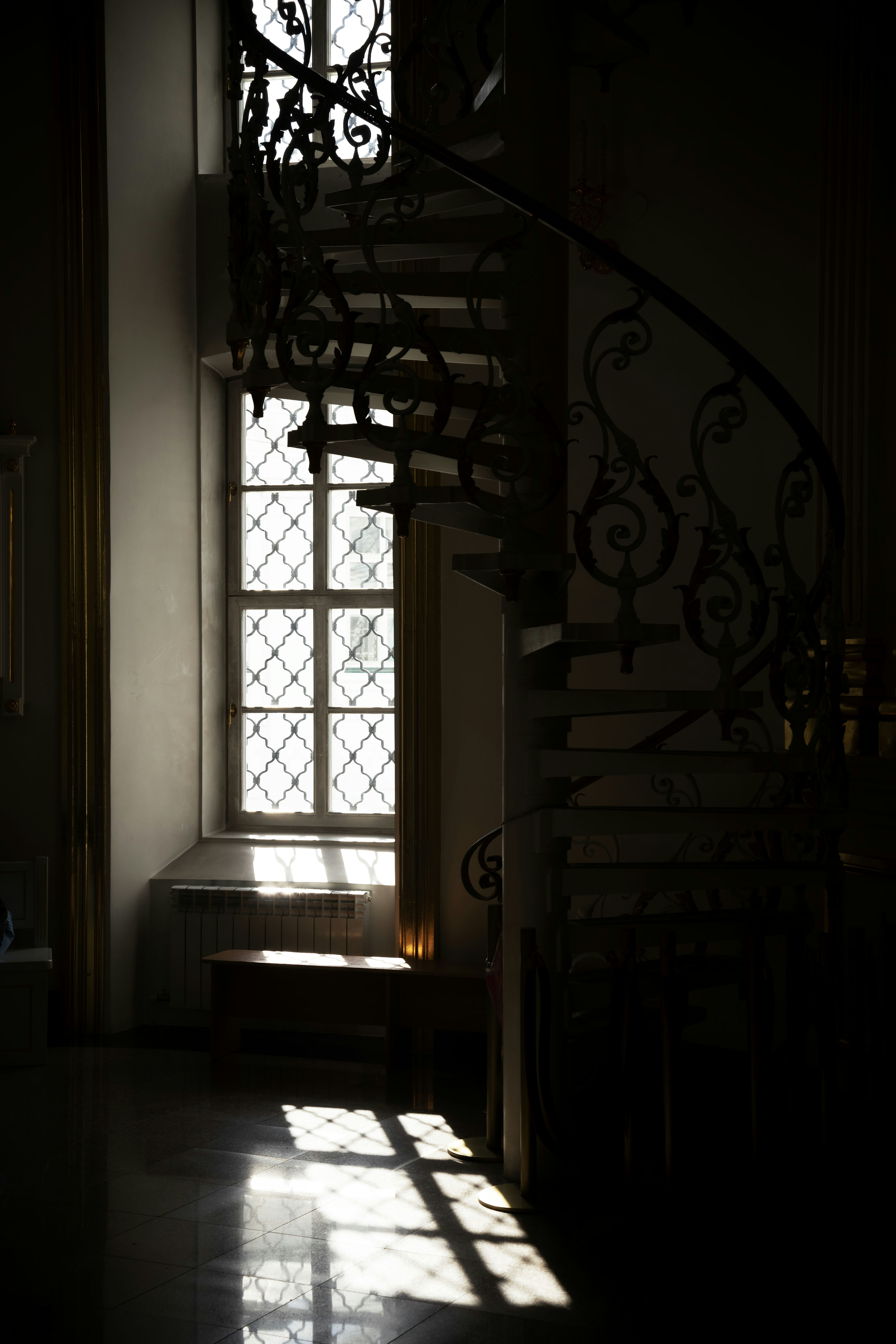 Sunlit Window and Wrought-iron Staircase in a Dim Hallway