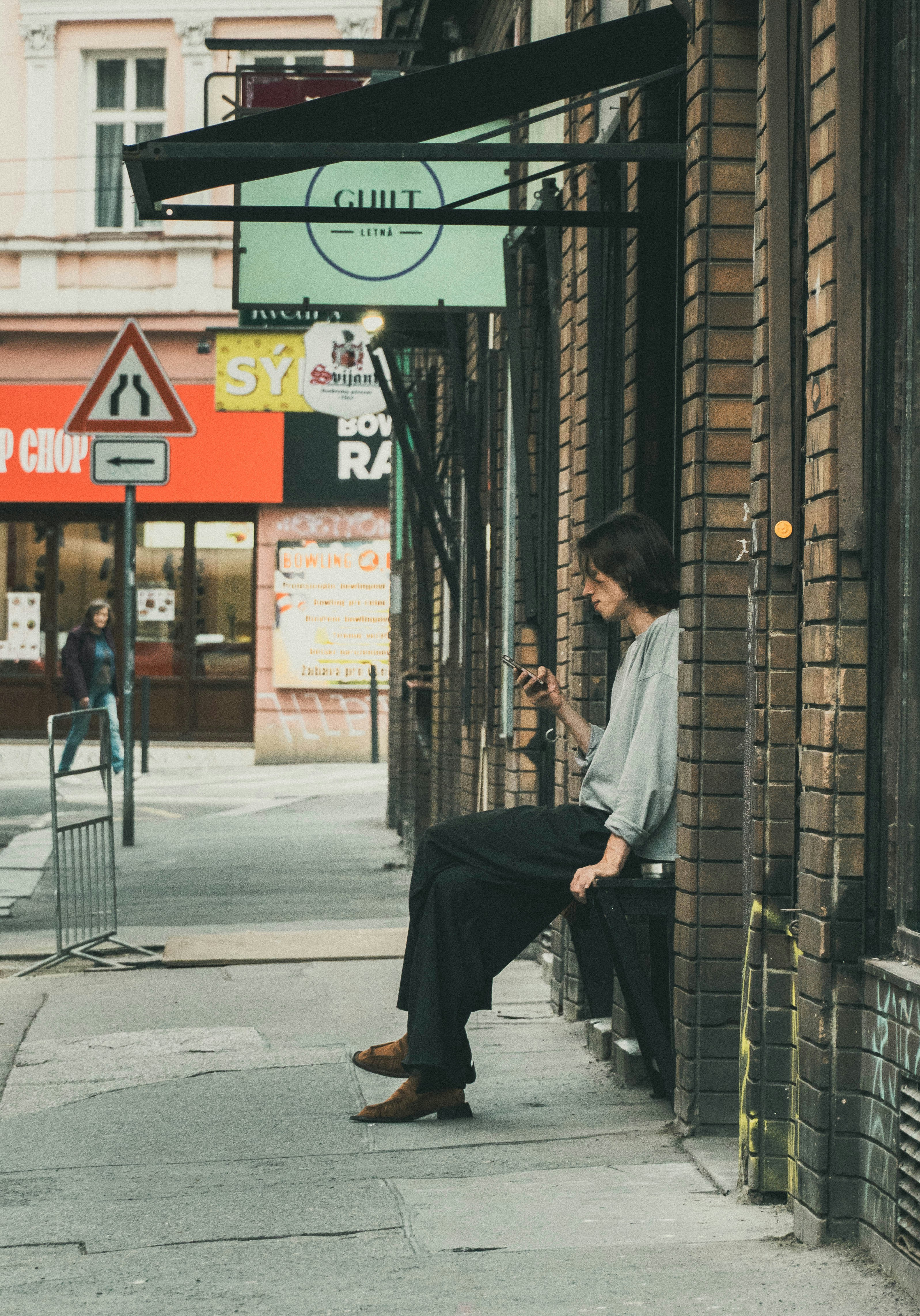 Sitting on the City Edge: A Solo Moment Amid Storefronts