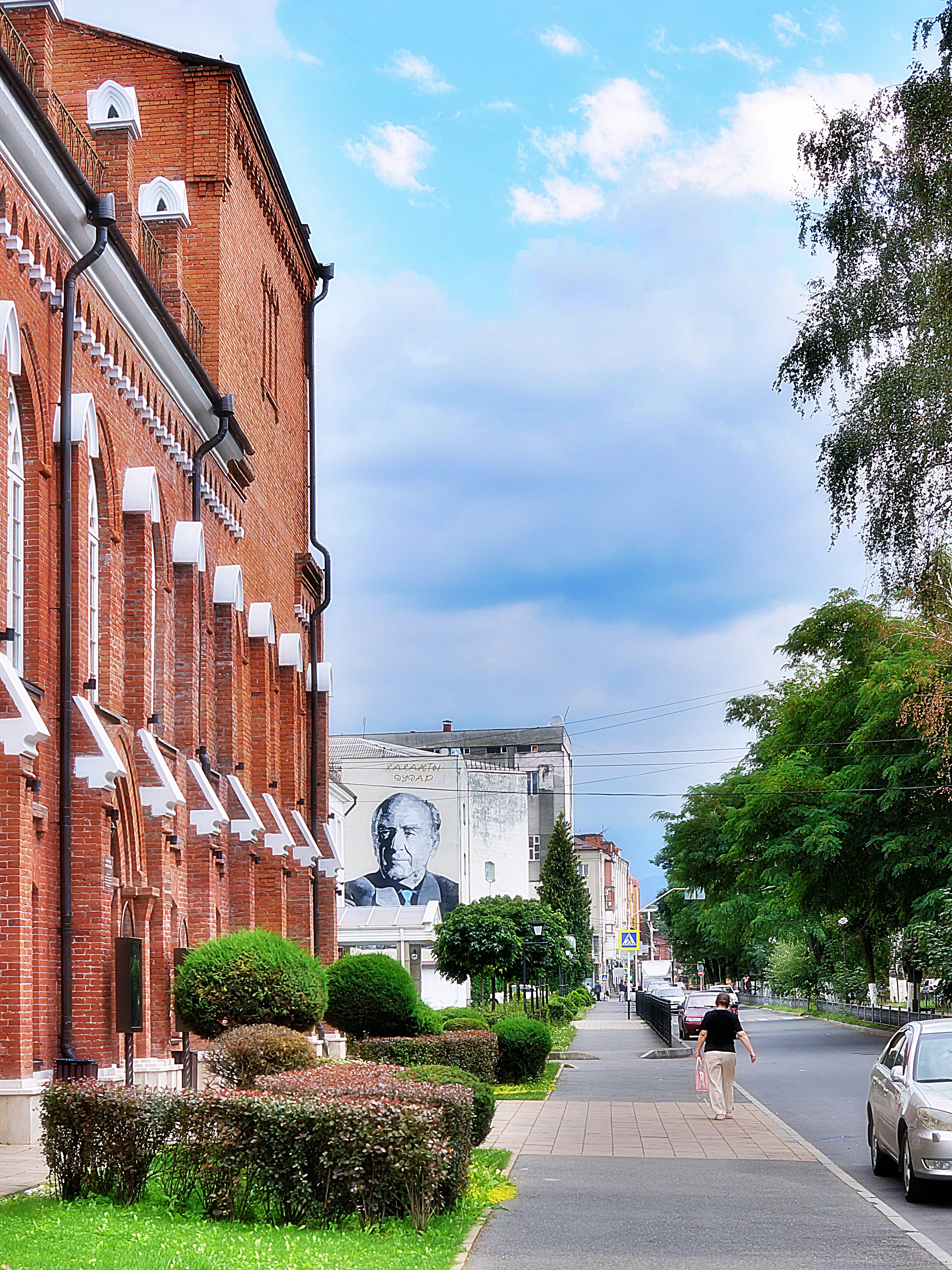 Portrait on the Wall: A Quiet City Street Framed by Brick and Green
