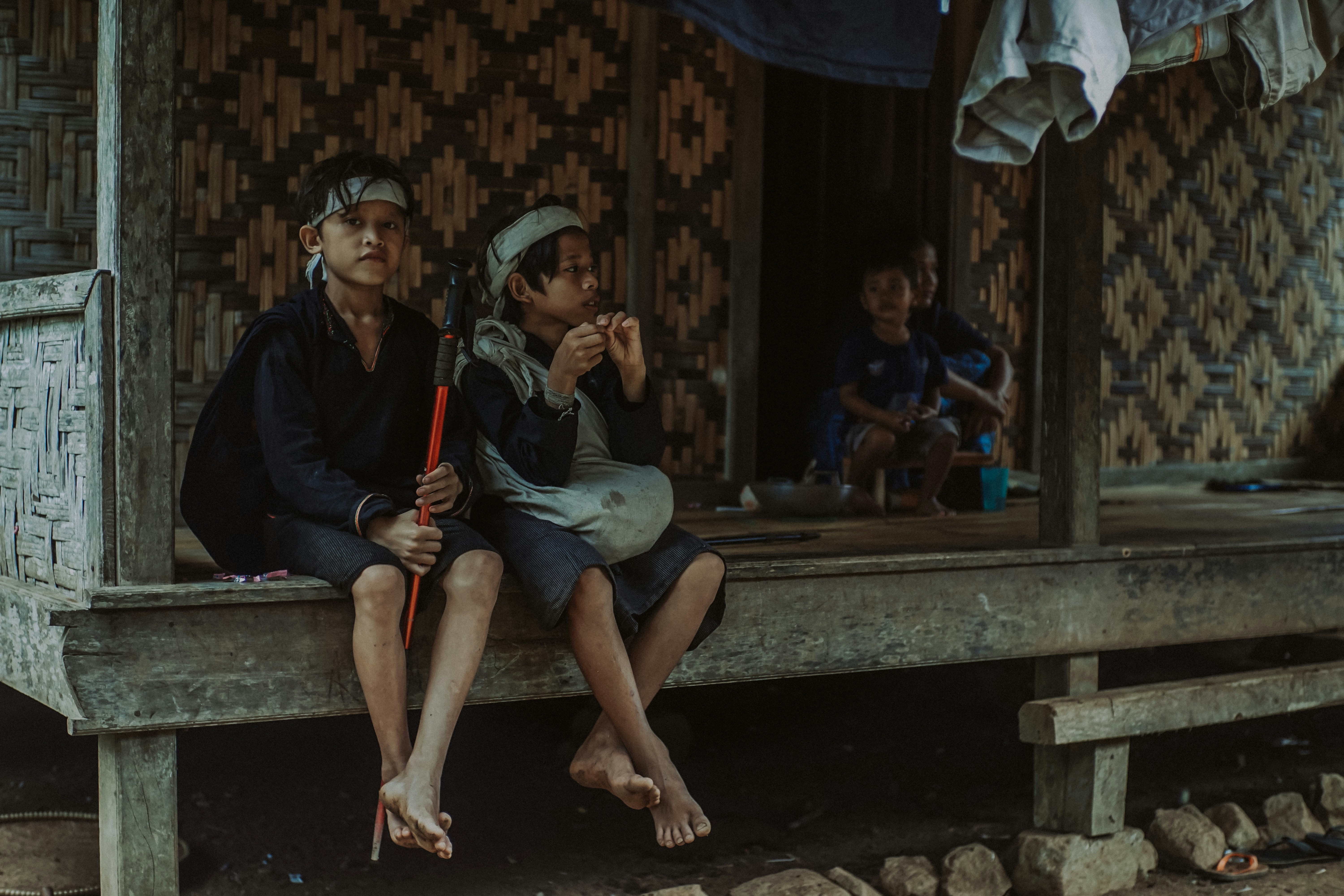 Children on a weathered veranda, shared moment over a maker’s tools