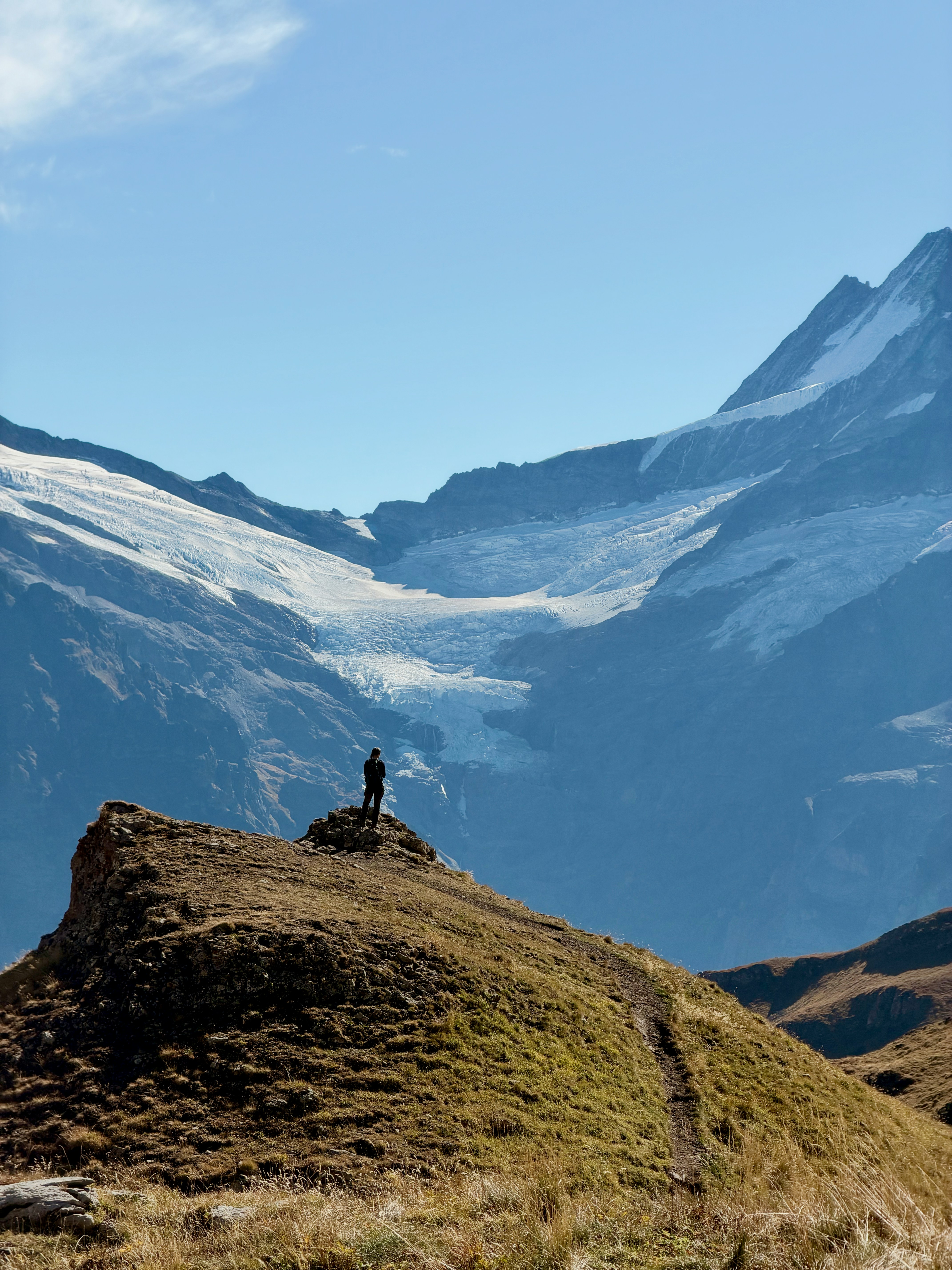  Summit Stride: A lone explorer on a windswept ridge beneath towering icefields