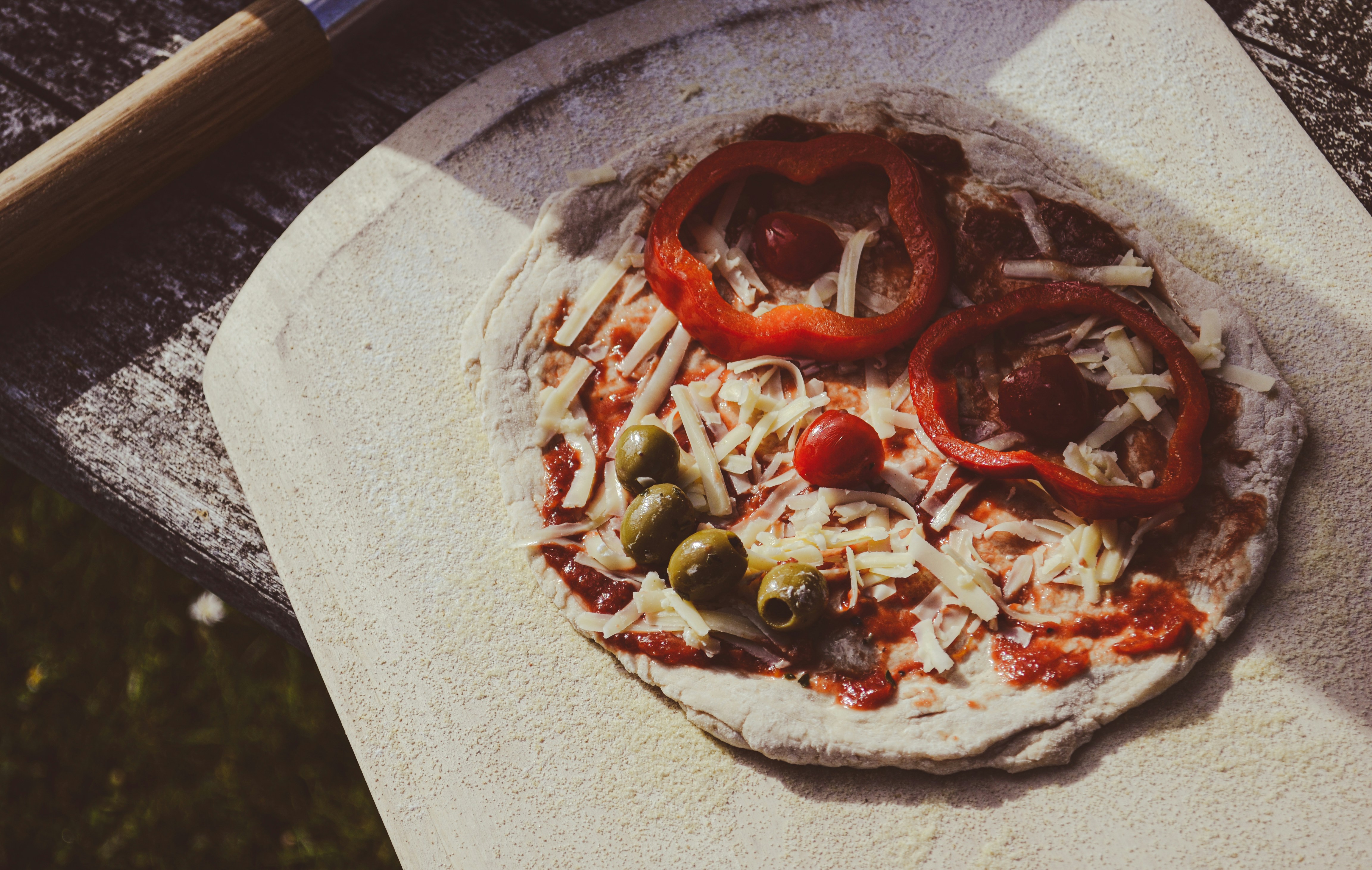 DIY Wood-fired Pizza: Pepperoni Rings and Green Olives on a Dusty Plate
