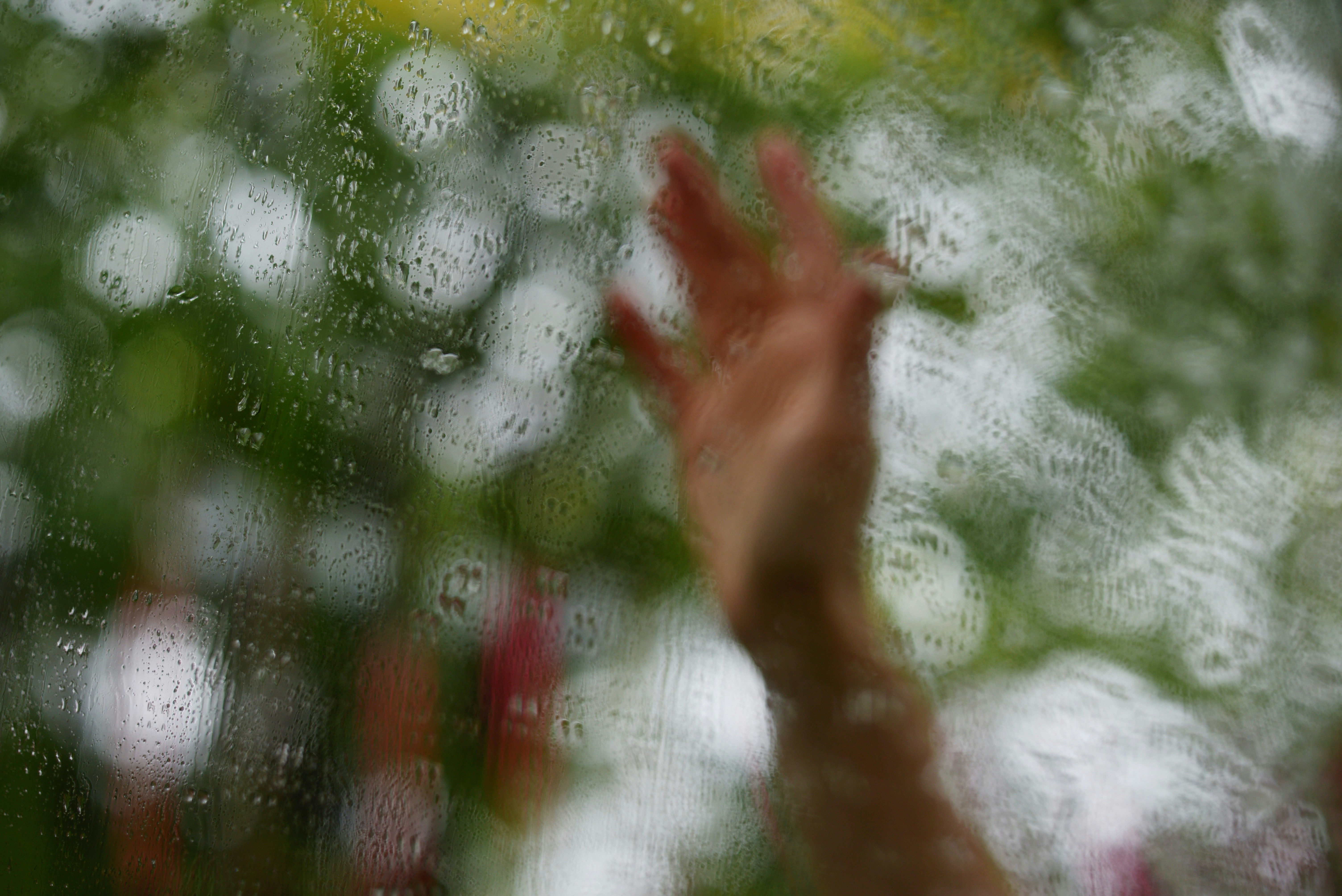 Hands Reaching Through a Rainy Glass Screen