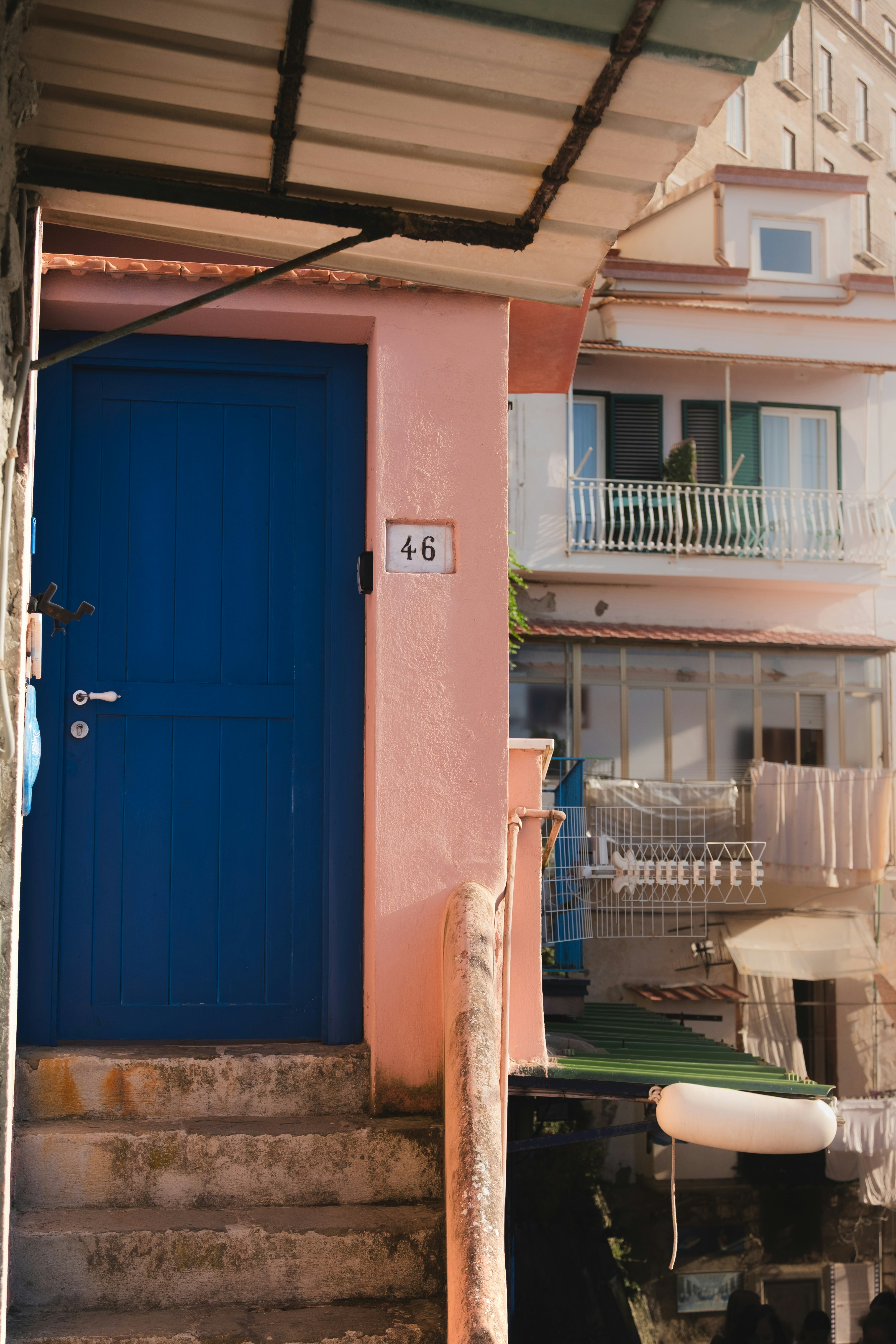 Blue Door, Peach Wall: A Quiet Sunlit Stairwell Scene
