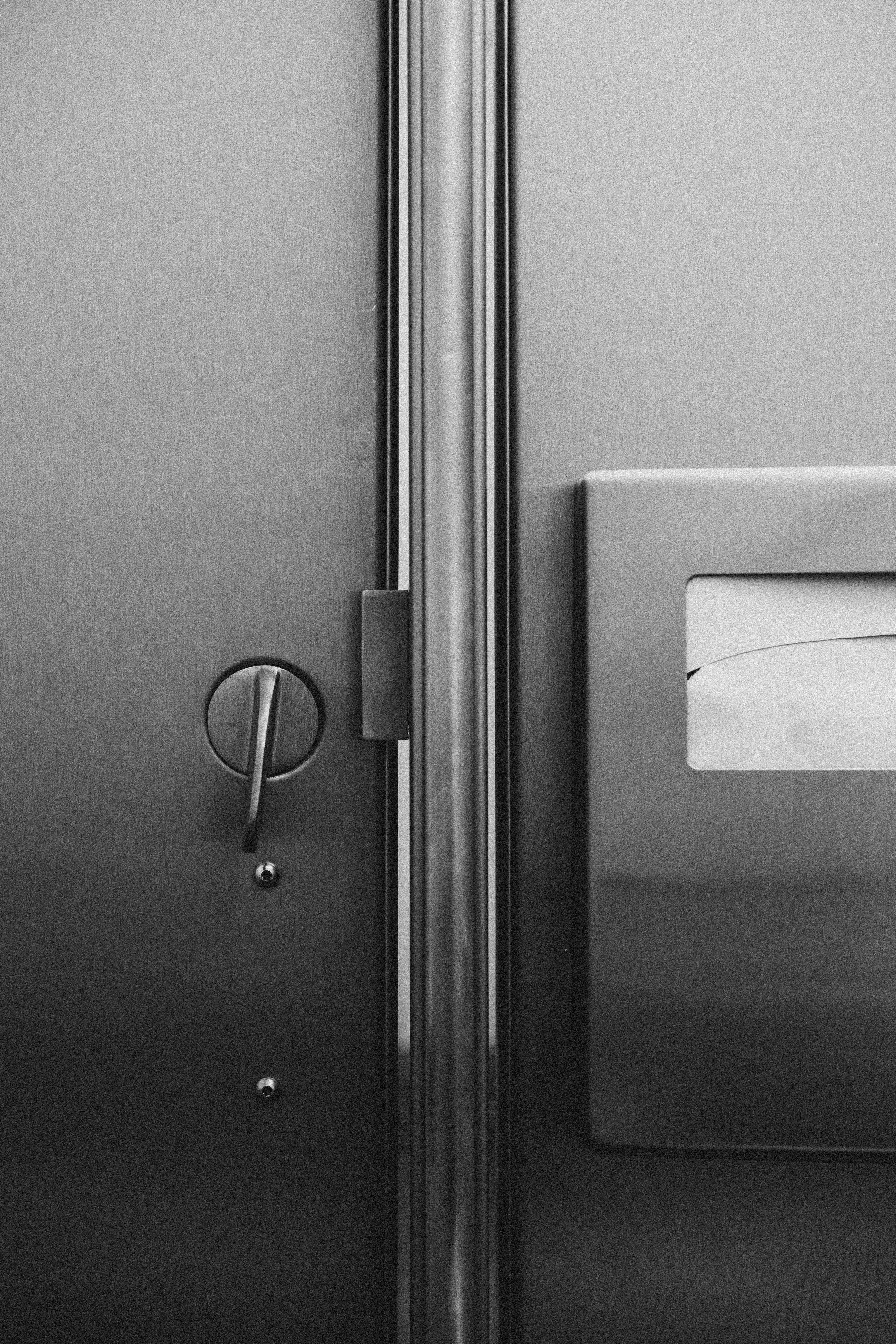 A black and white close-up of a metal door with a handle and a paper towel dispenser