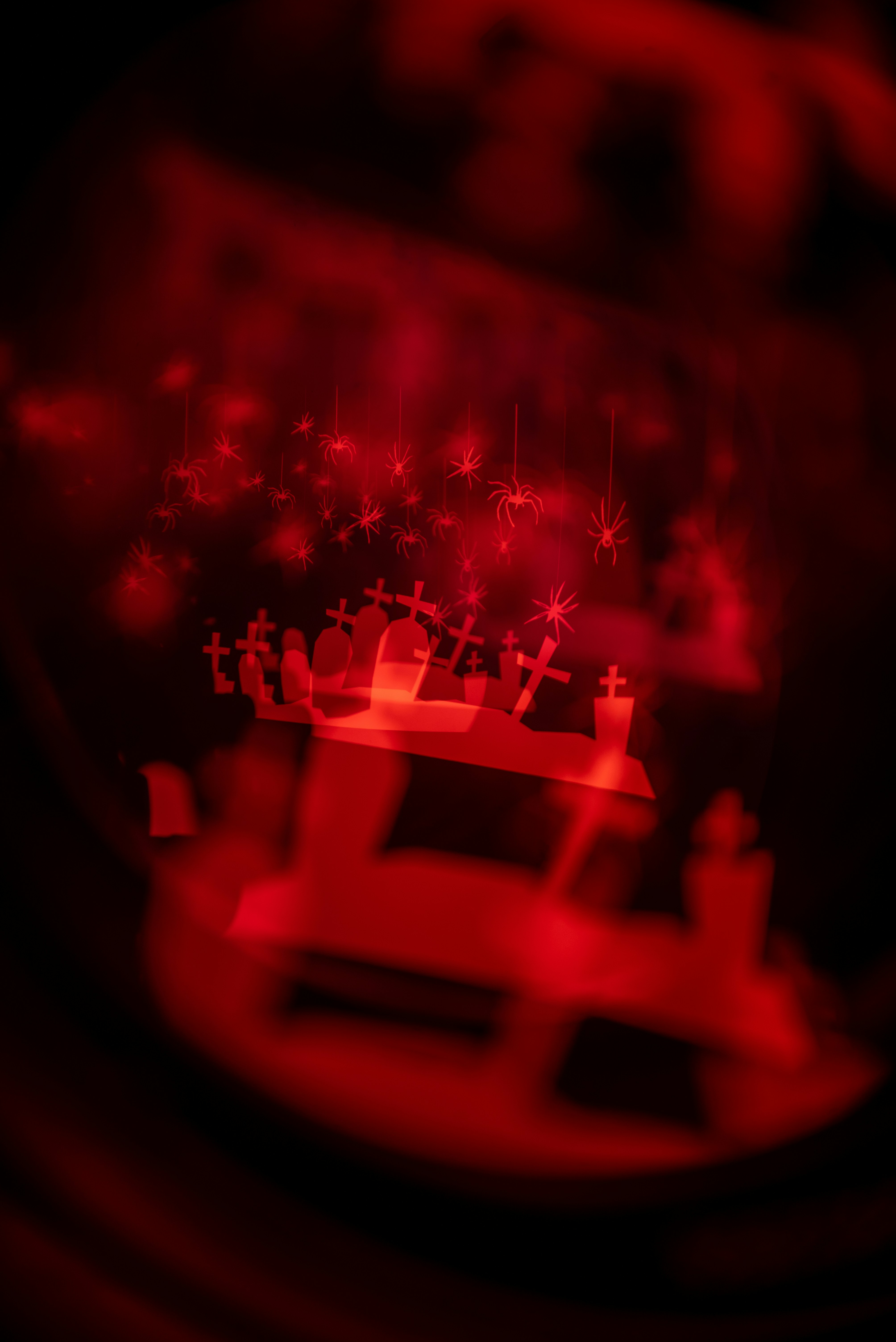 Architectural silhouettes of crosses and tombs bathed in crimson blur, evoking a spectral cemetery scene.
