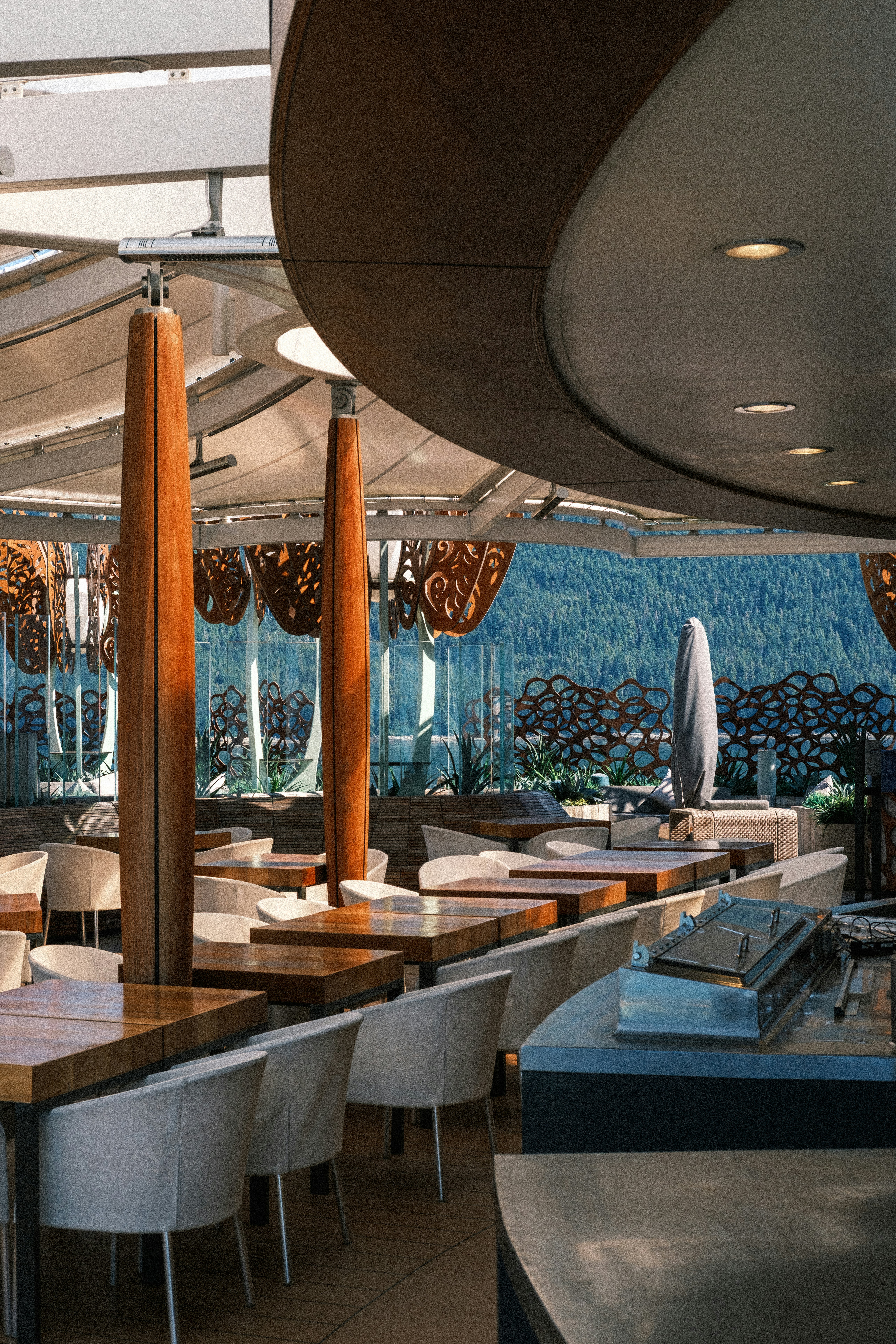 Lounge under a curved canopy: timber columns and sculpted lattice wall at dusk