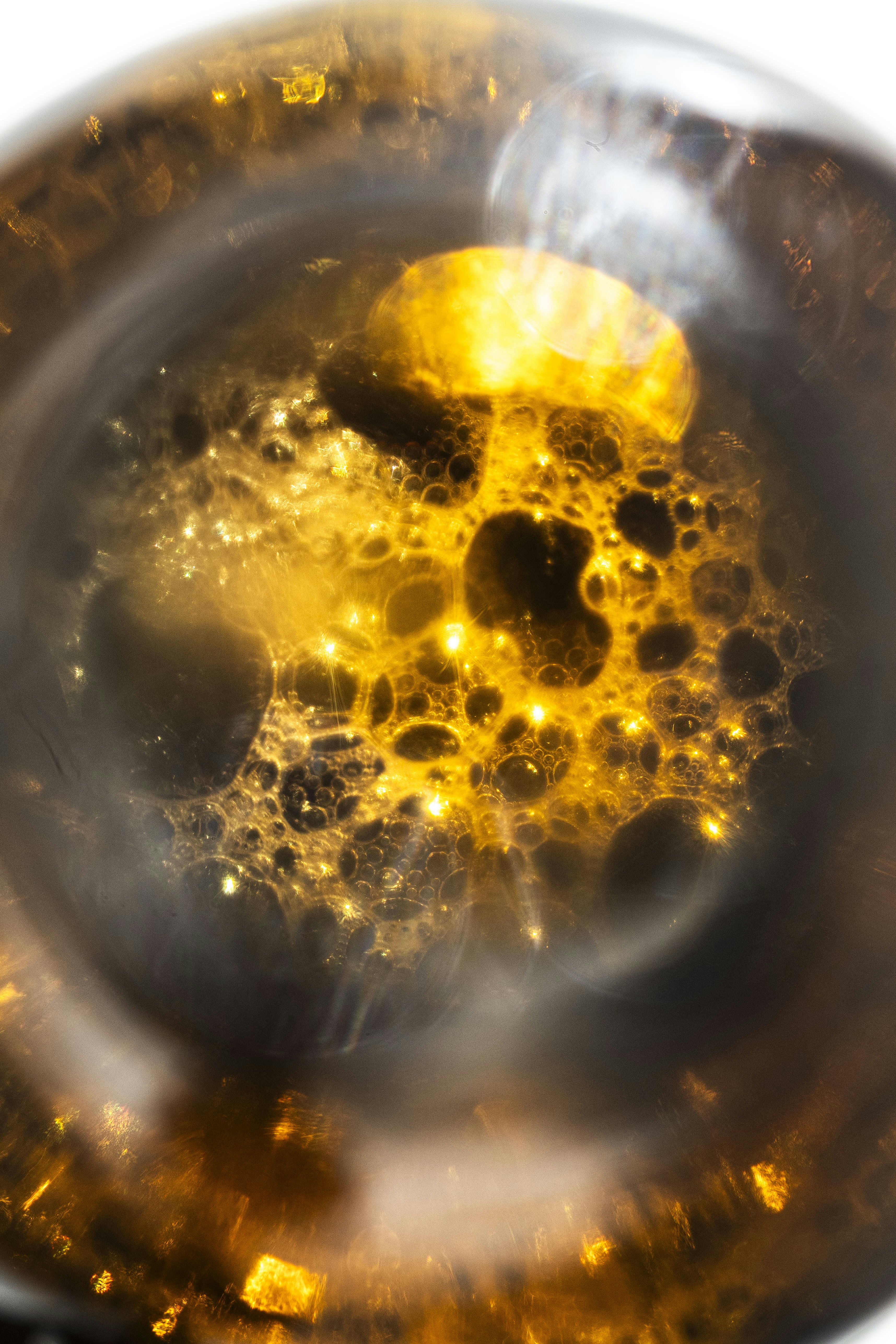 Golden Bubbles in a Glass: Abstract Caramel Glow Through a Teacup