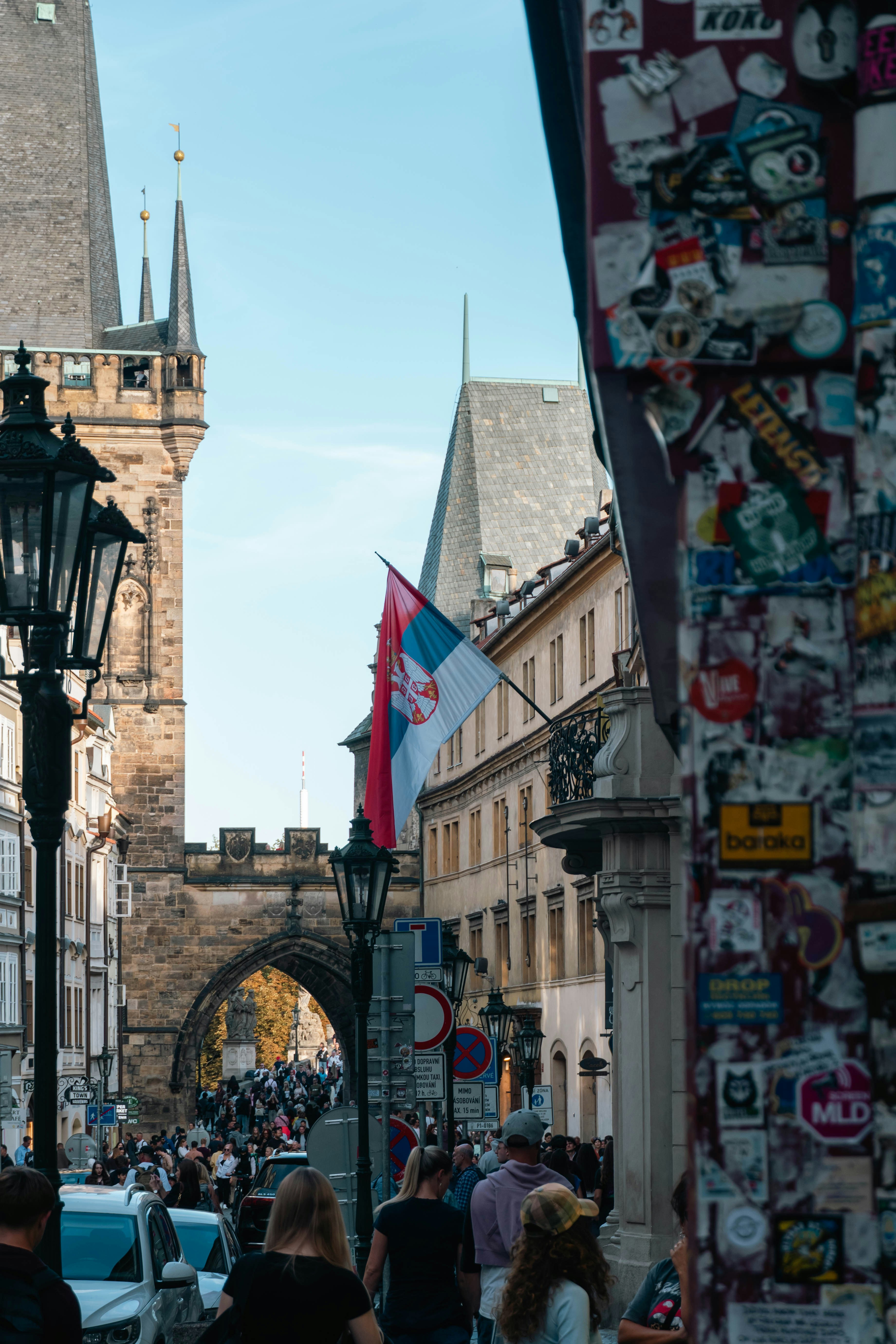 Flag over the ancient arch: a European street framed by towers and a crowd