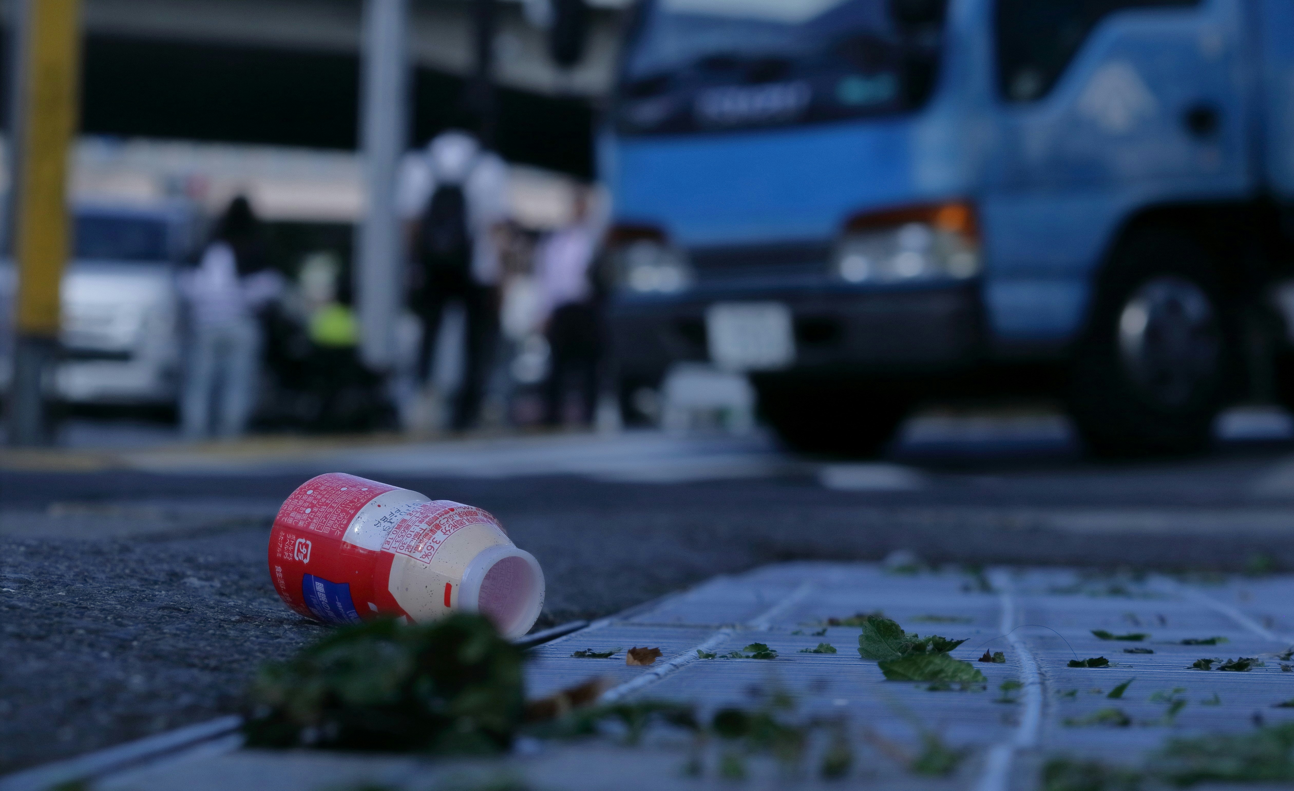 Discarded cup under the city’s wake: a quiet scene of litter and distant activity