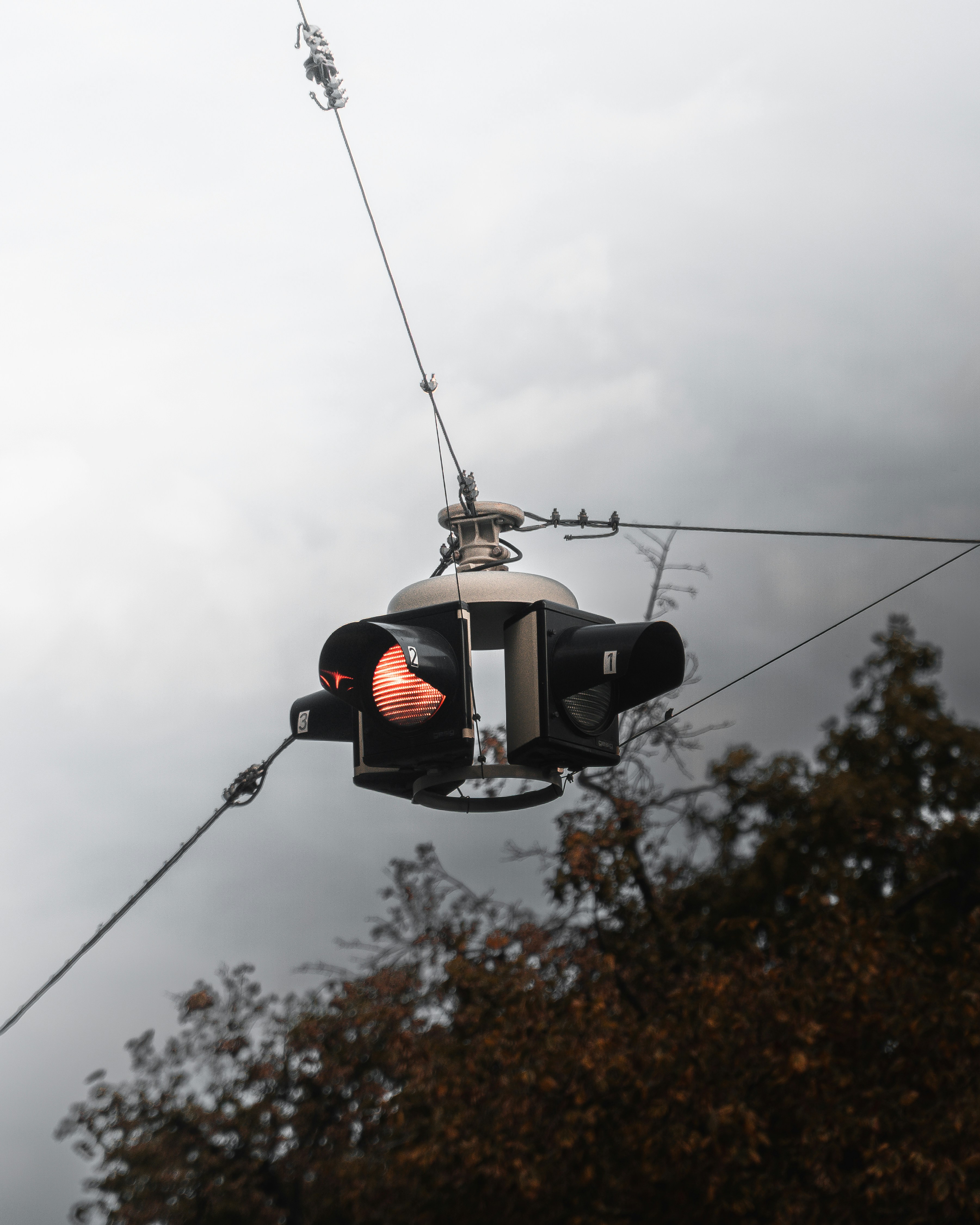 Suspended Signal: A Traffic Light Spanning Wires Under a Brooding Sky