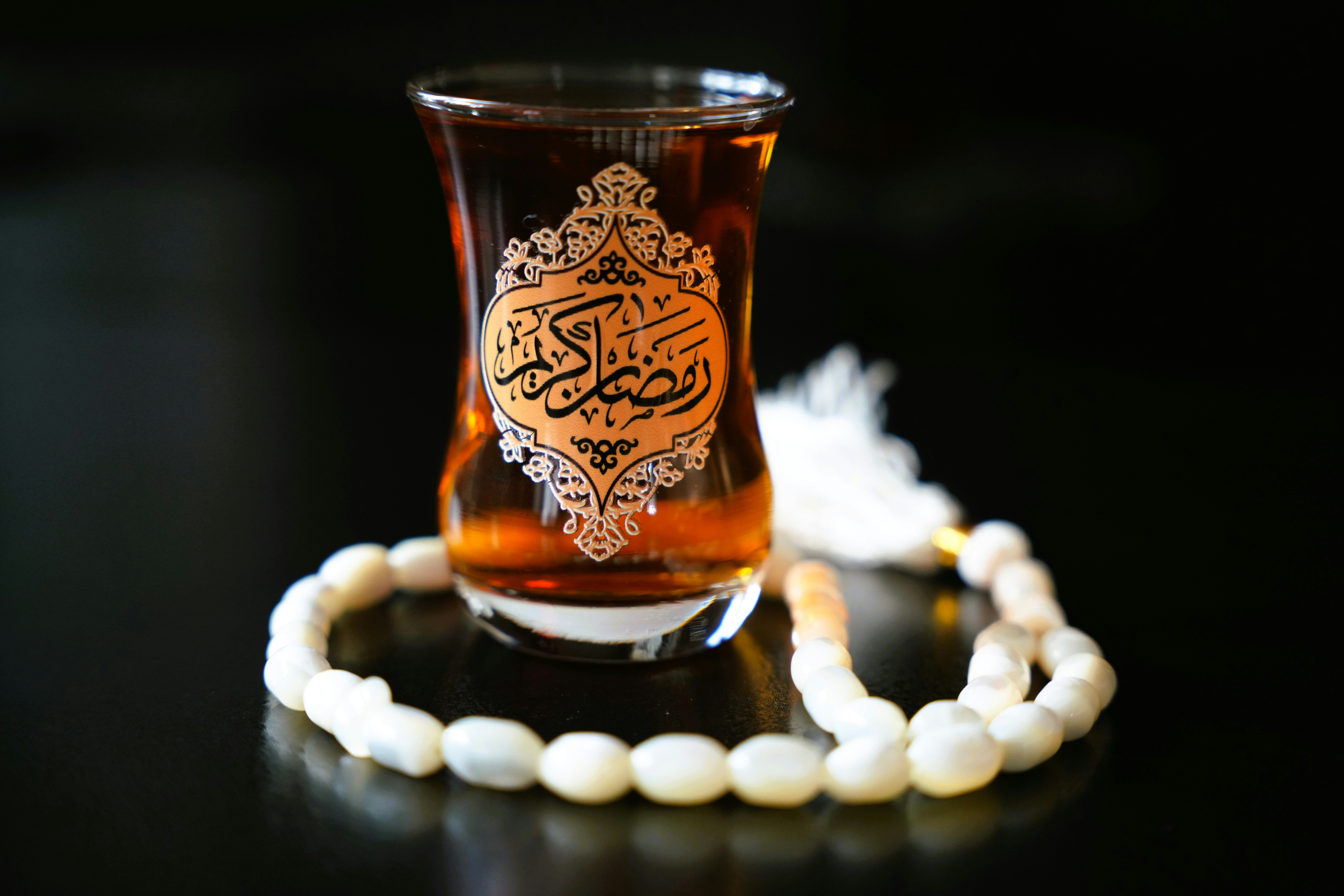Tea Glass with Ornate Etching resting beside a pearl-lit garland