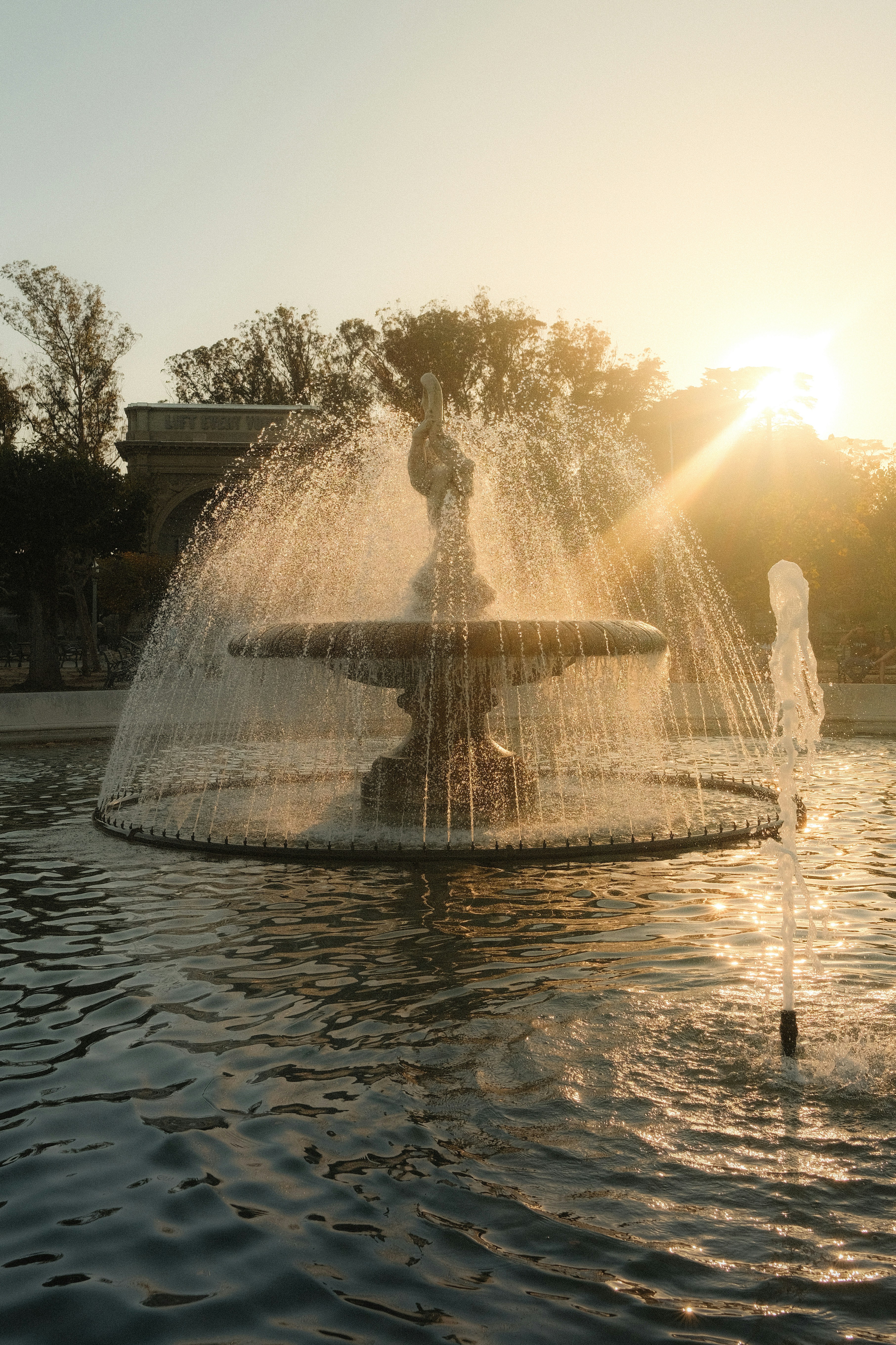 Sunlit Cascade: A Historic Fountain Framed by Dappled Light