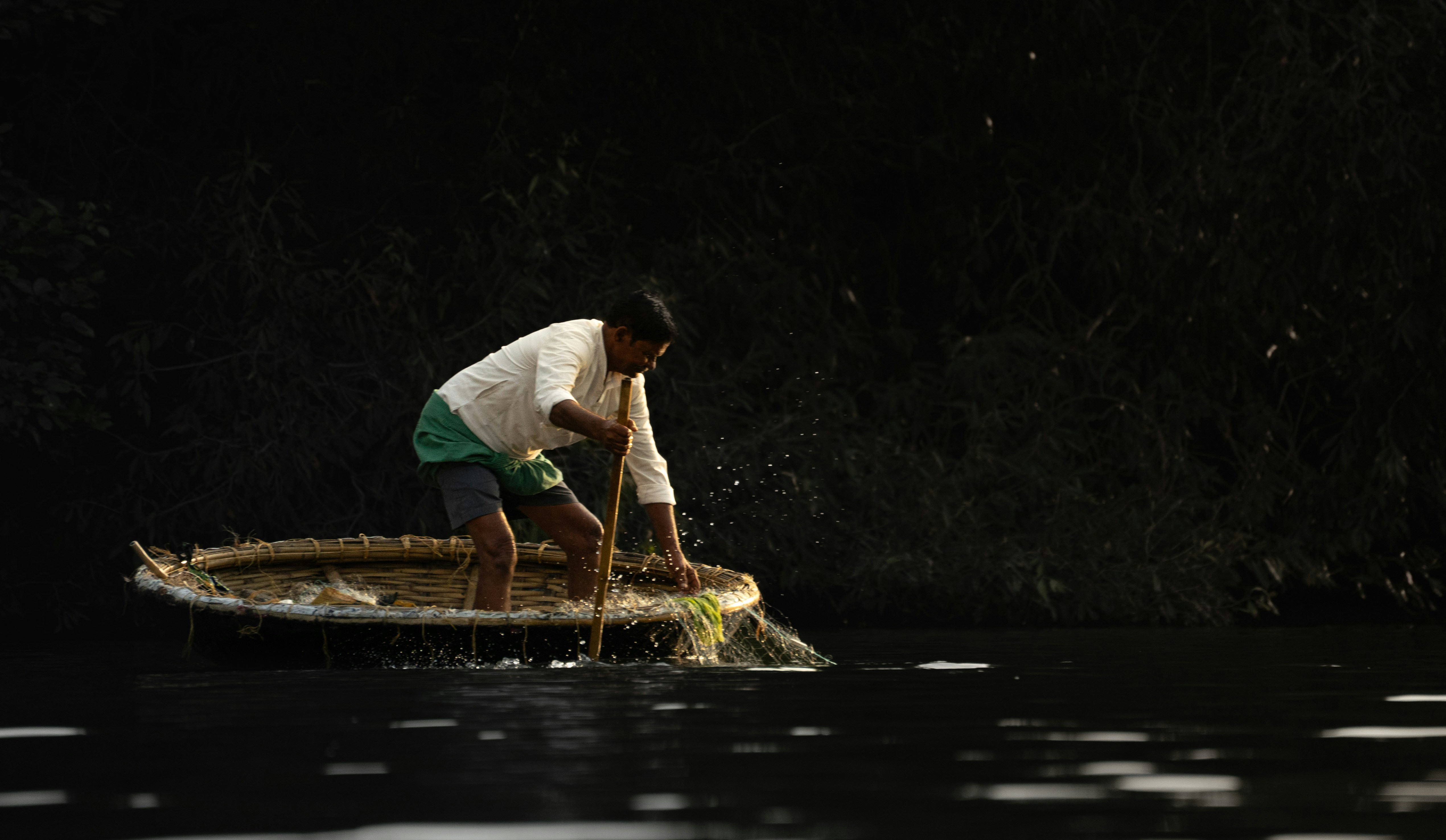 Diverging Ripple: A Man Paddles a Simple Boat Through Quiet Waters