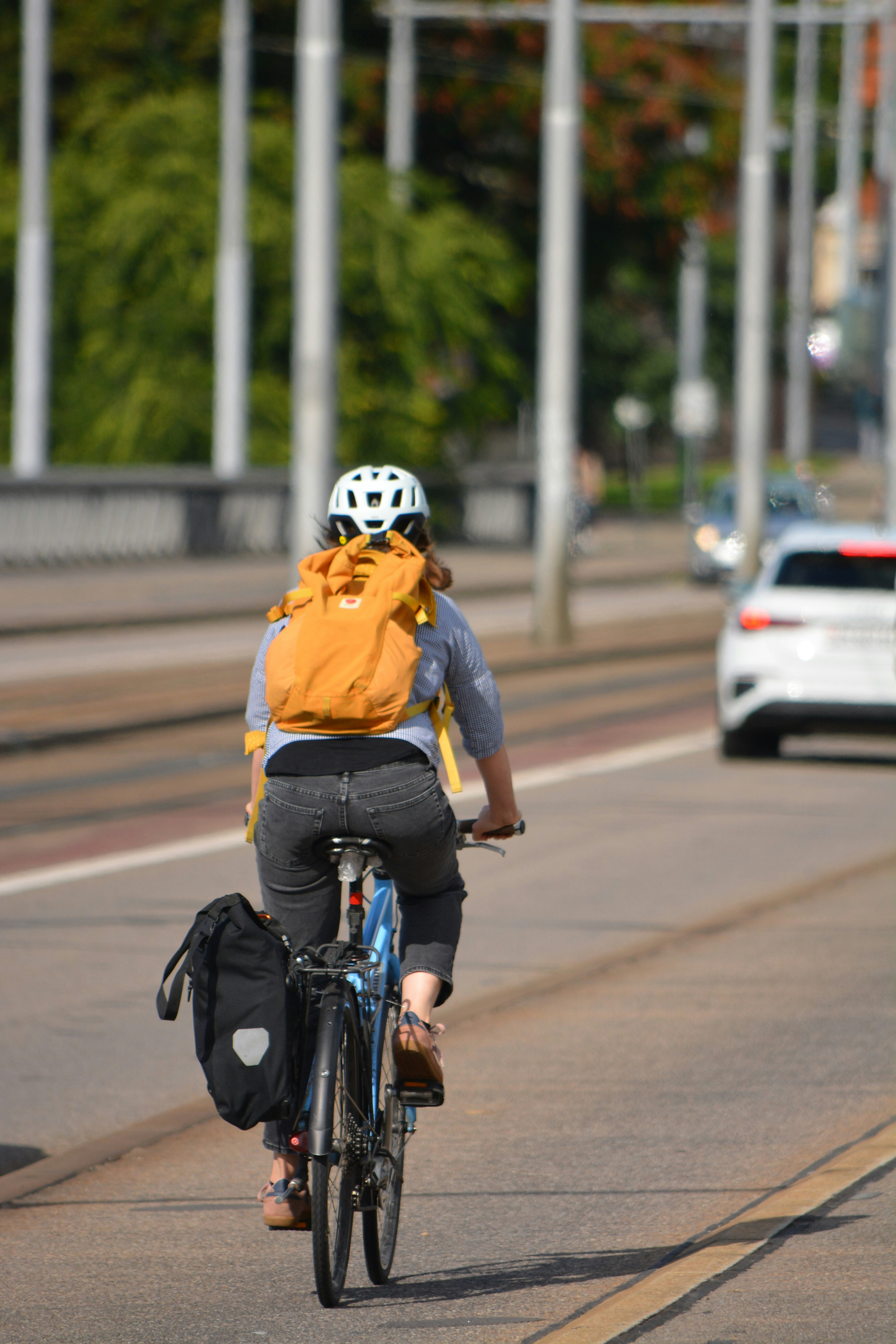 Pedal Pursuit: A Cyclist with Bright Orange Backpack Rides Through Urban Artery
