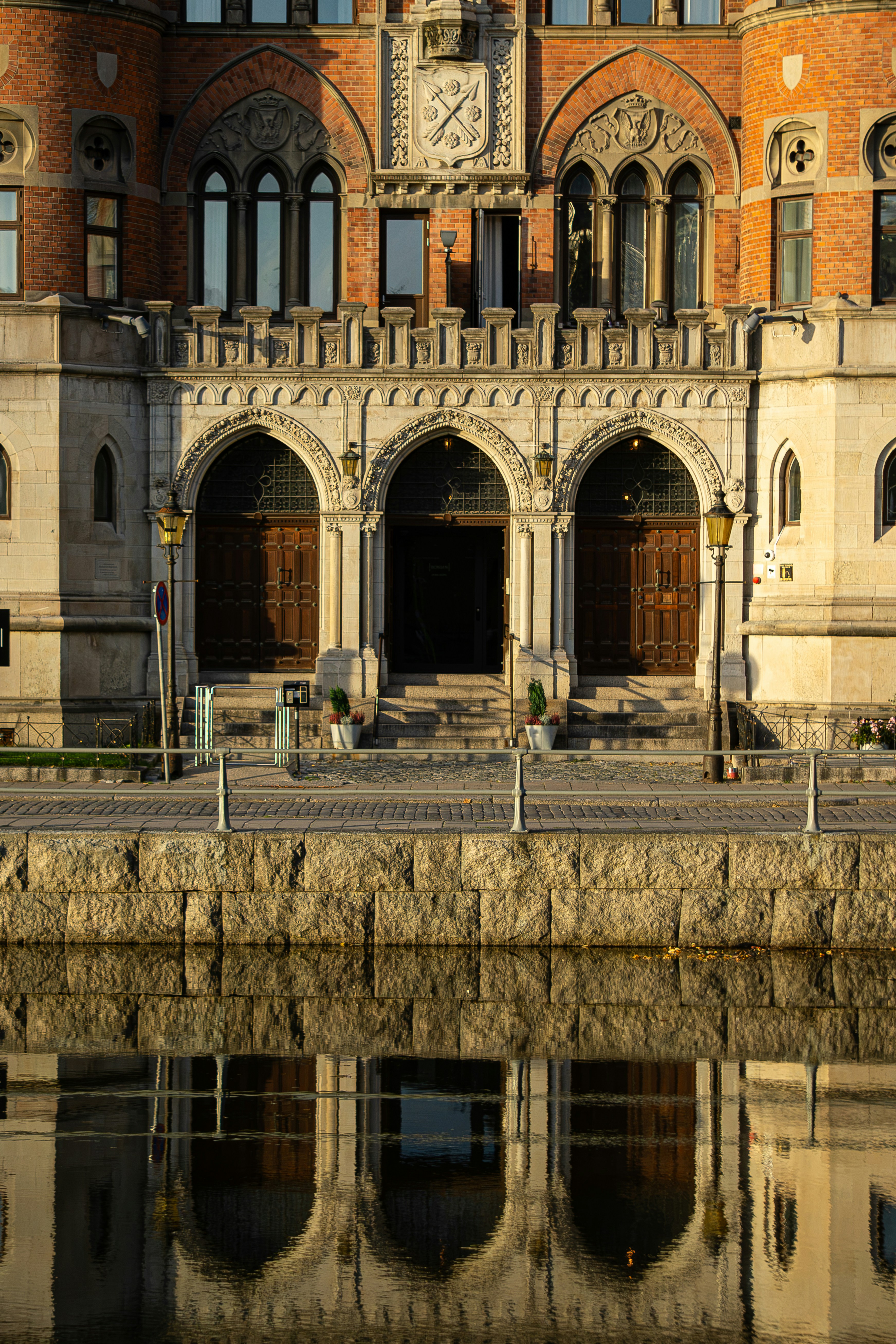 Arched Riverside Entrance: Historic Brick Facade Reflected in Calm Waters