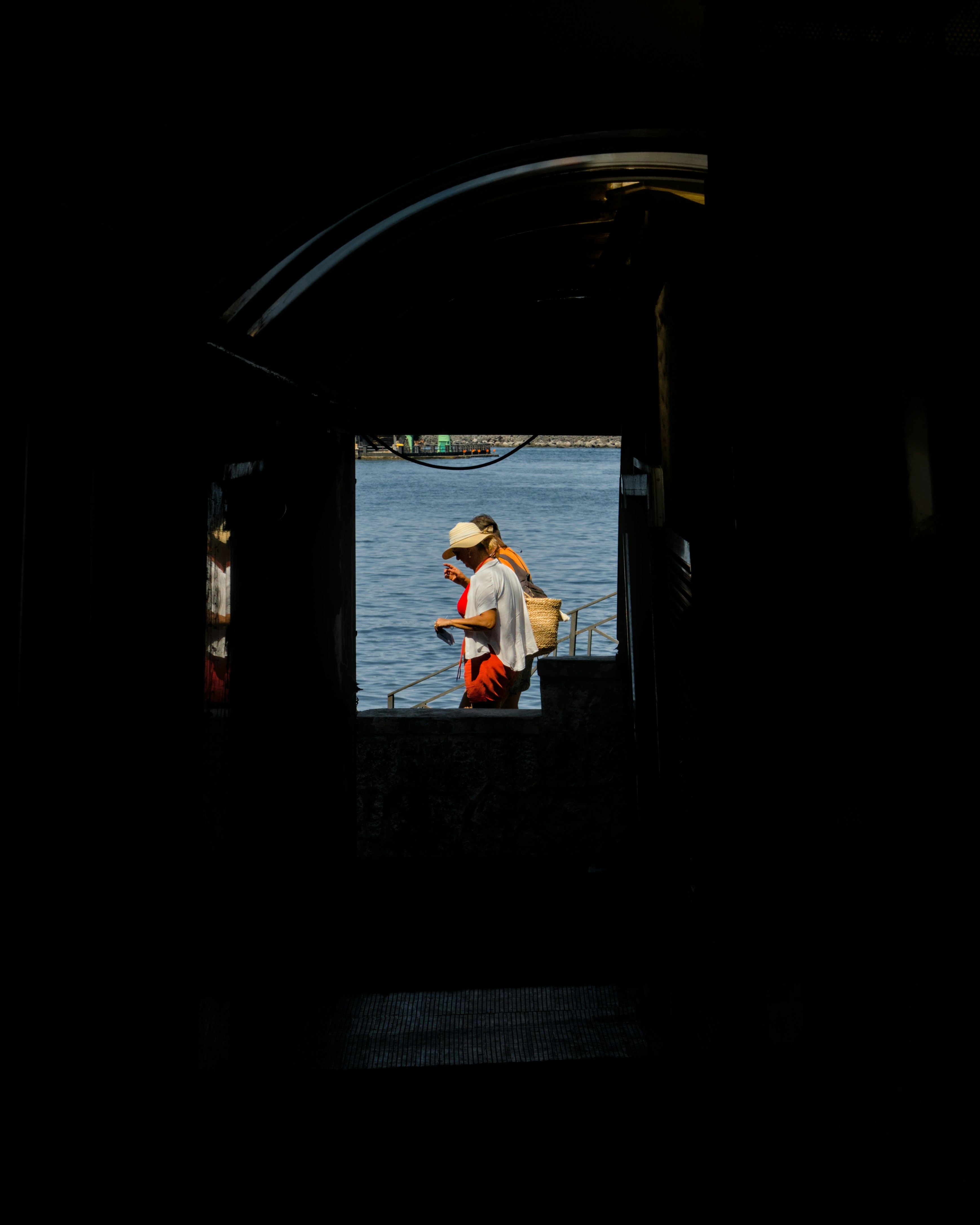 A Glimpse Through the Dock: Light, silhouette, and a Worker at the Water