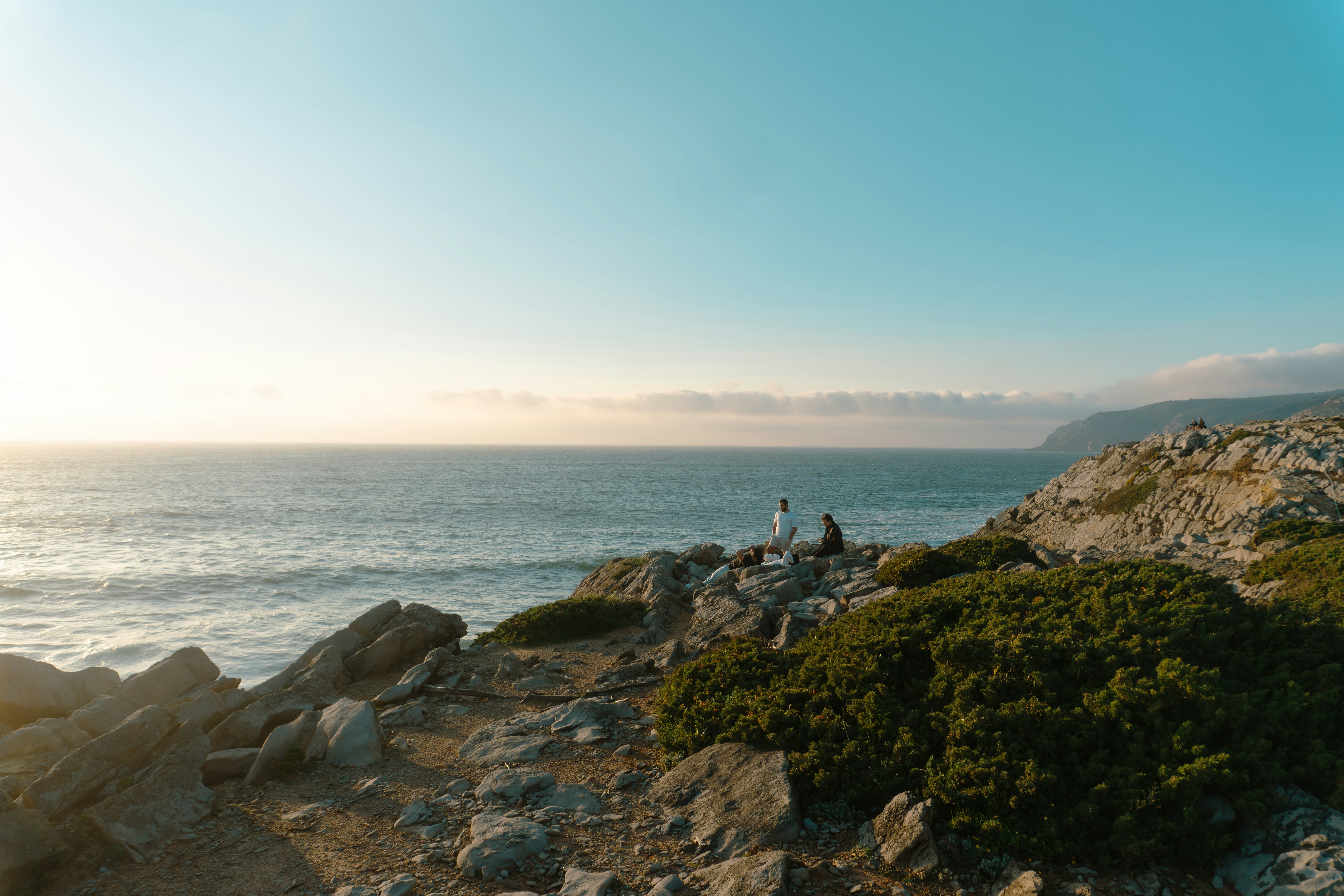Clifftop Silhouette: Travelers at Sunset Over the Quiet Sea
